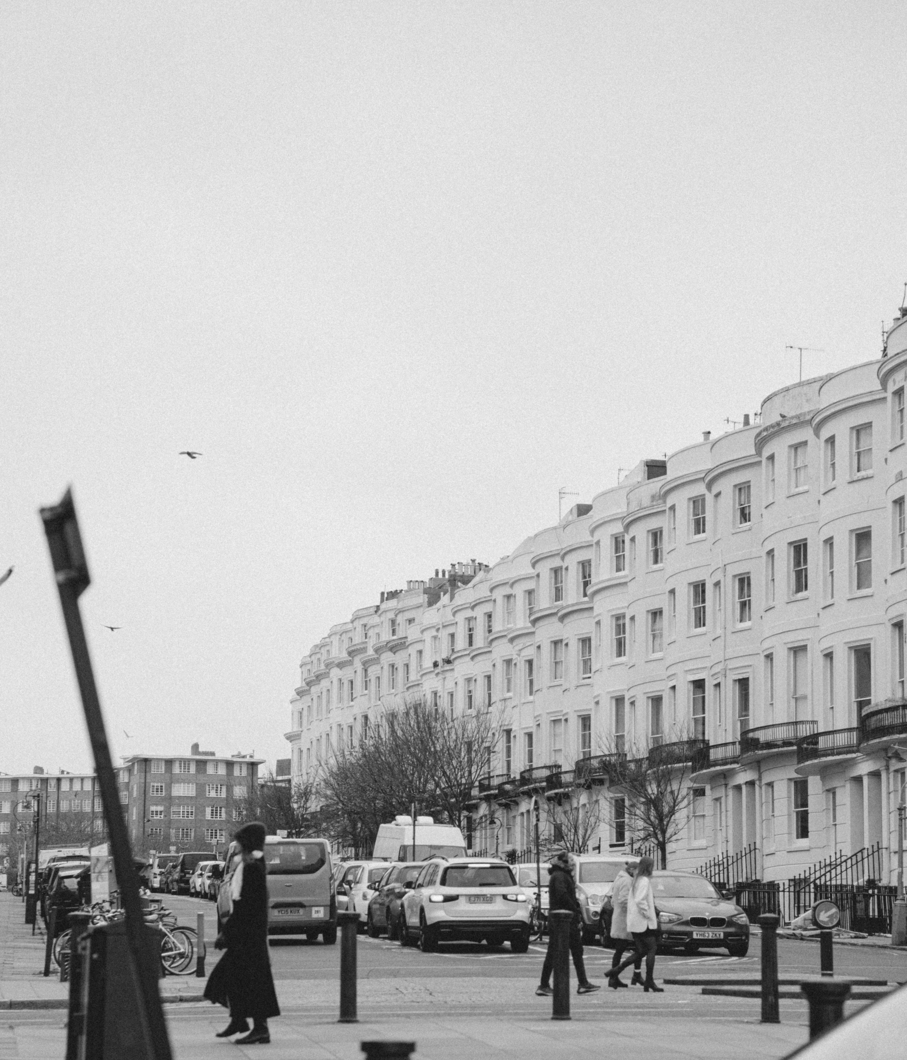 Monochrome Cadence: Pedestrians Along a Row of Townhouses