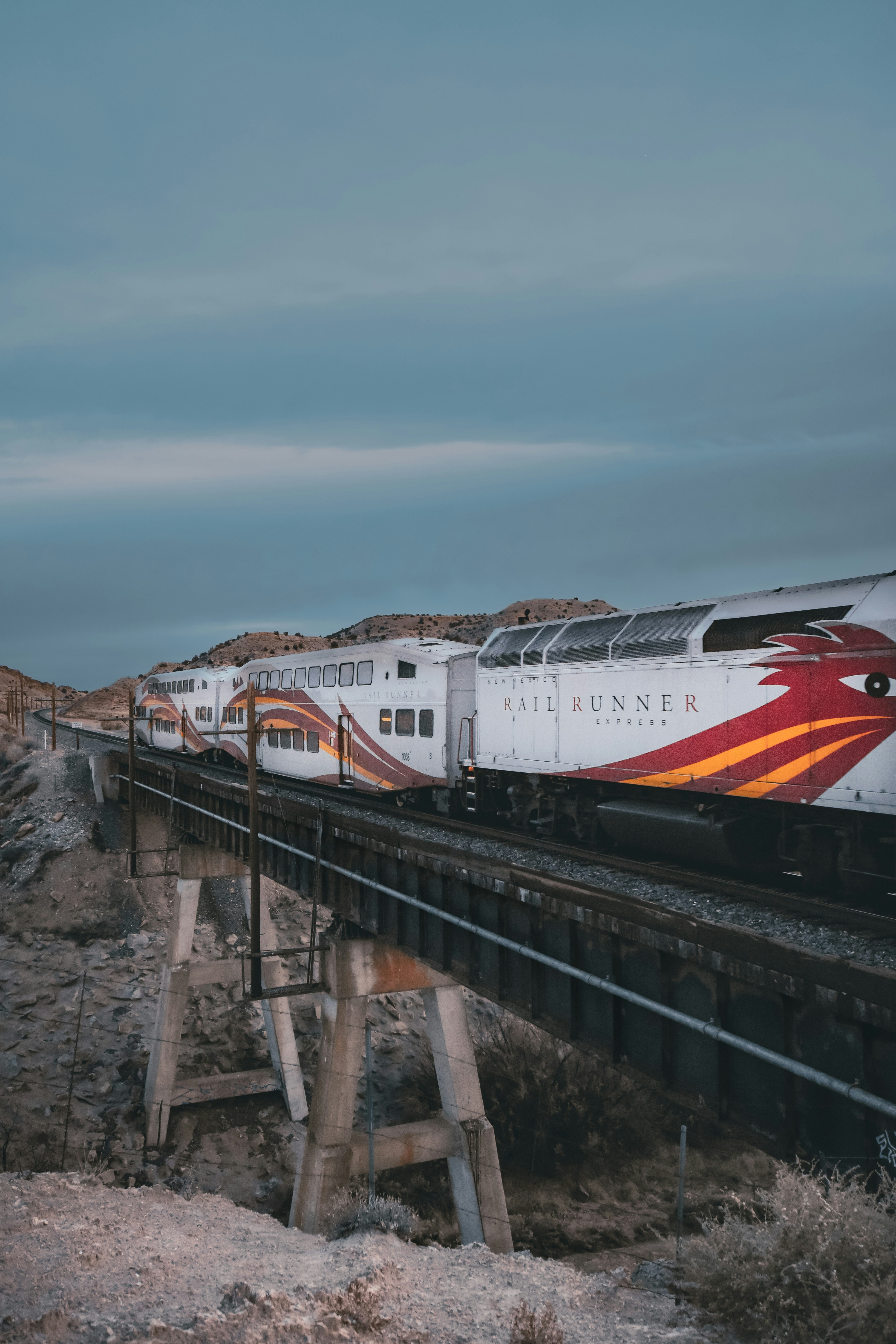 A train traveling over a bridge on a cloudy day photo – Free Train ...