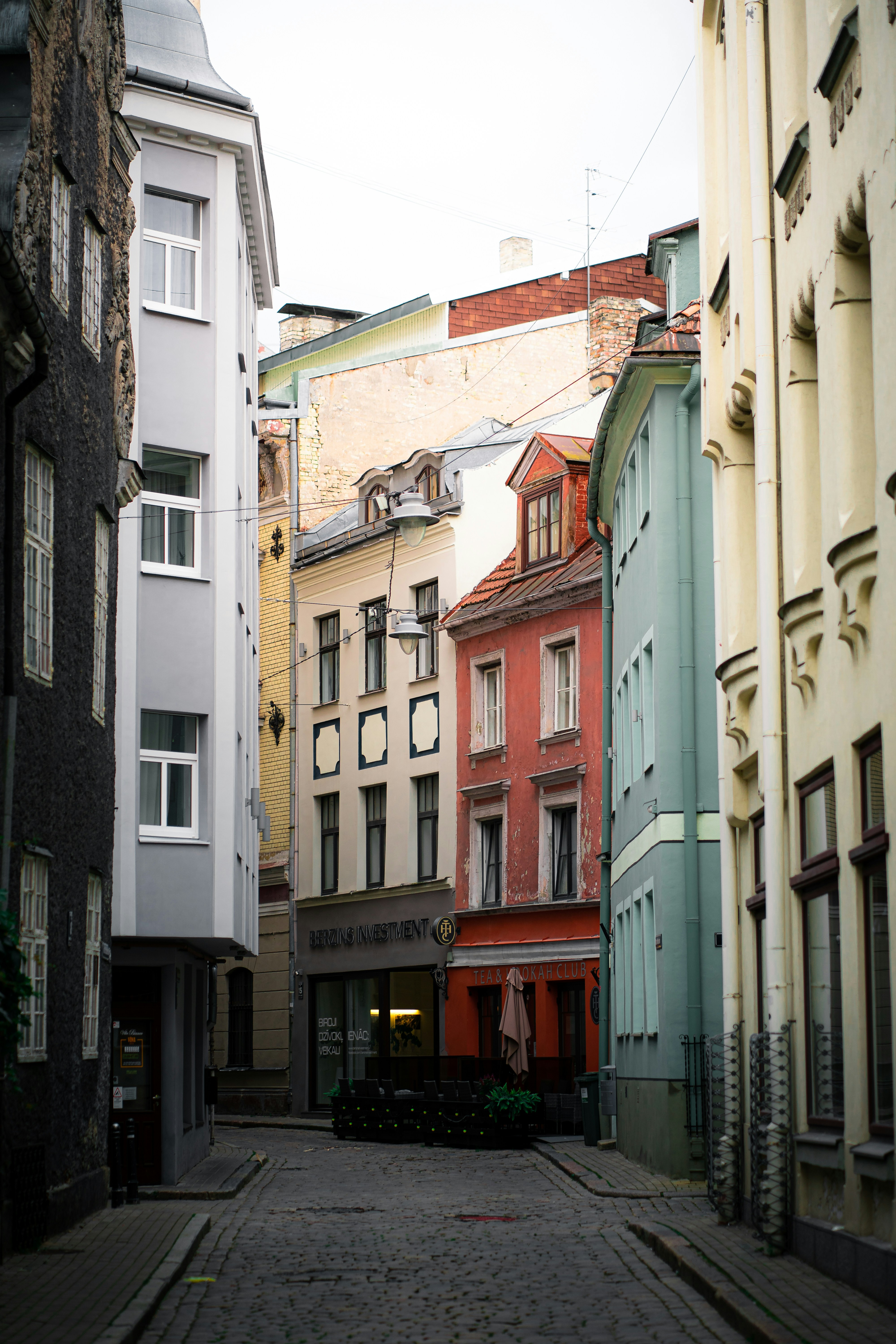 A narrow city street lined with tall buildings photo – Free Riga Image ...