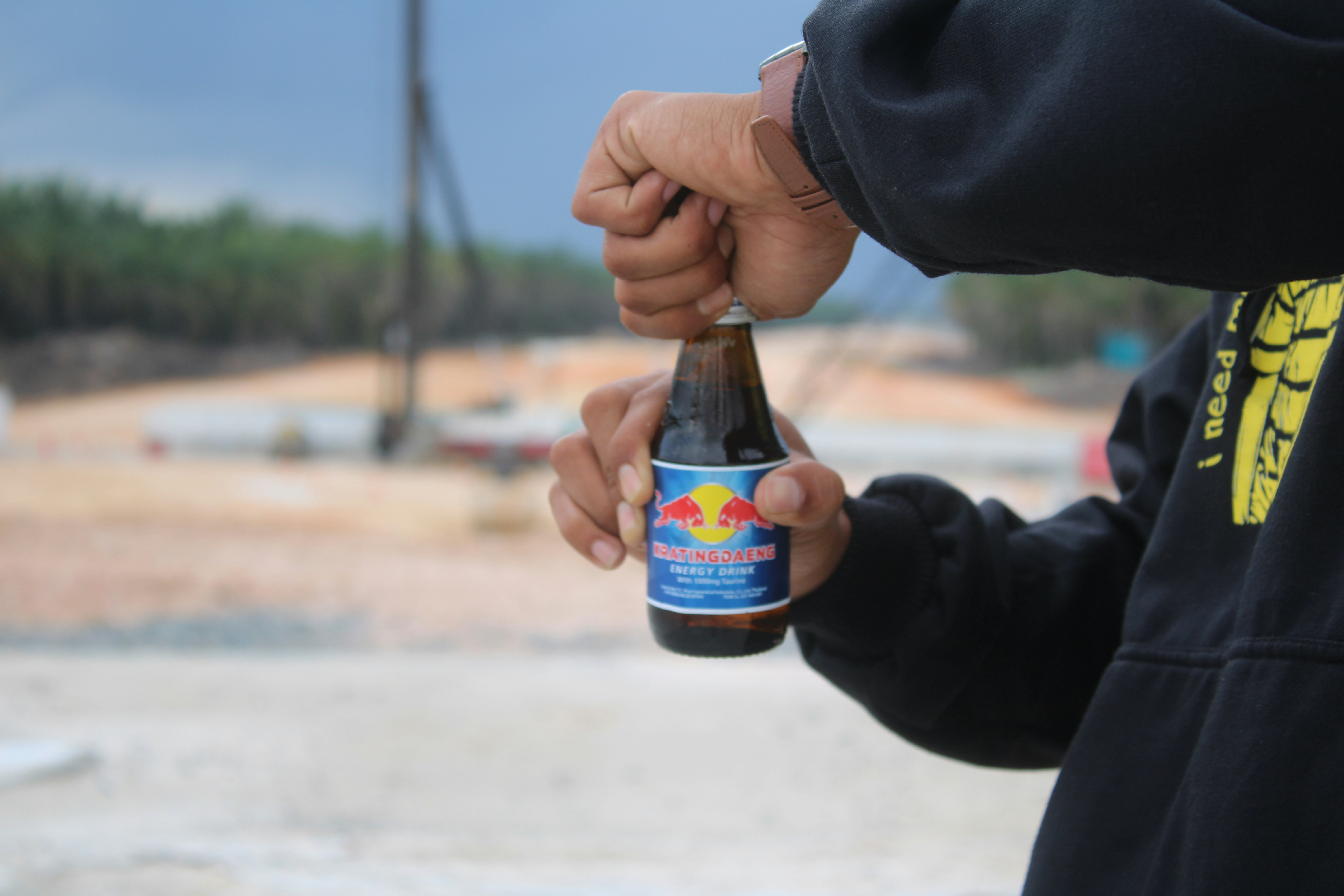 Coastal Grip: Craft Beer Clasp Against a Quiet Beach Blur