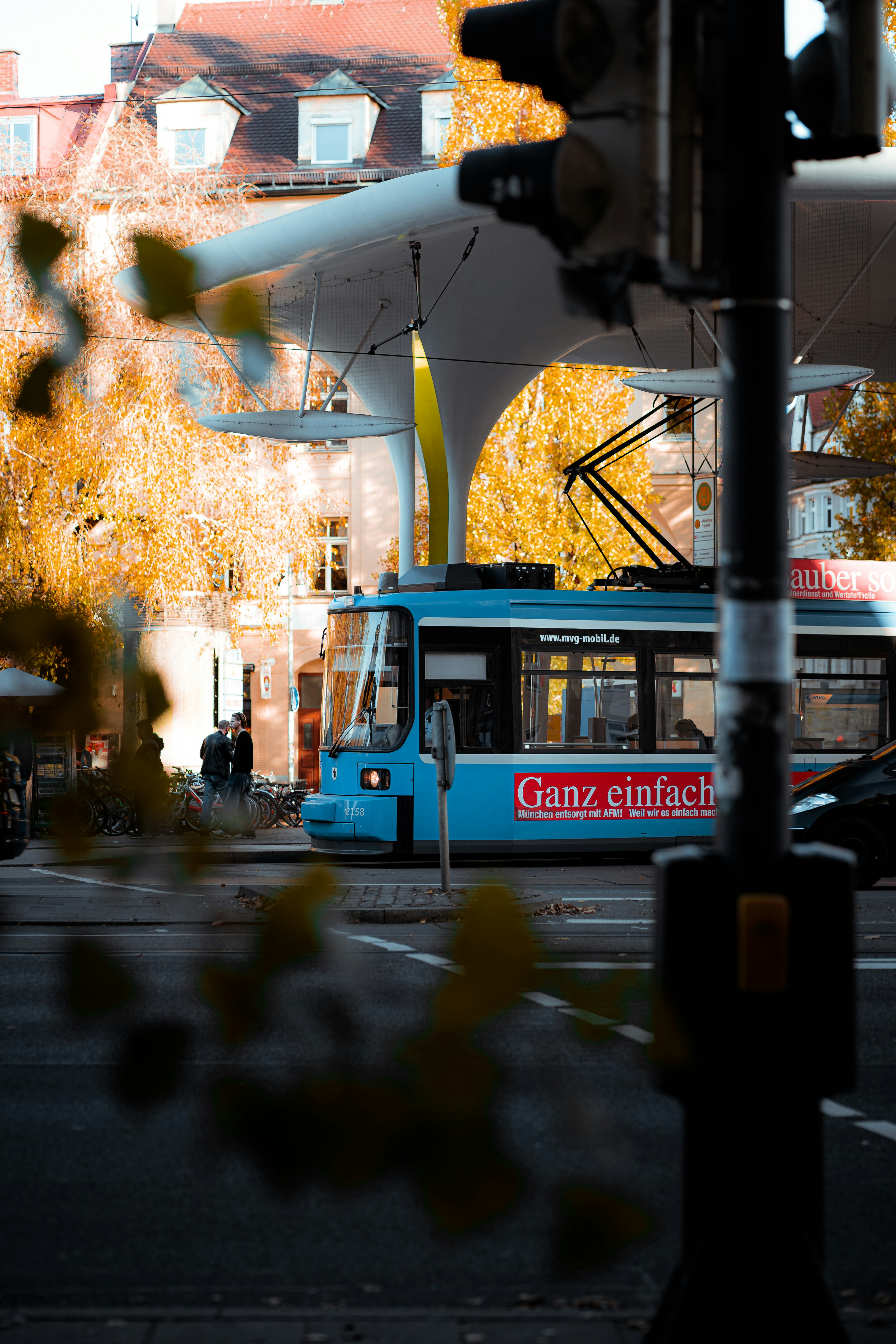 A blue bus driving down a street next to tall buildings photo – Free ...