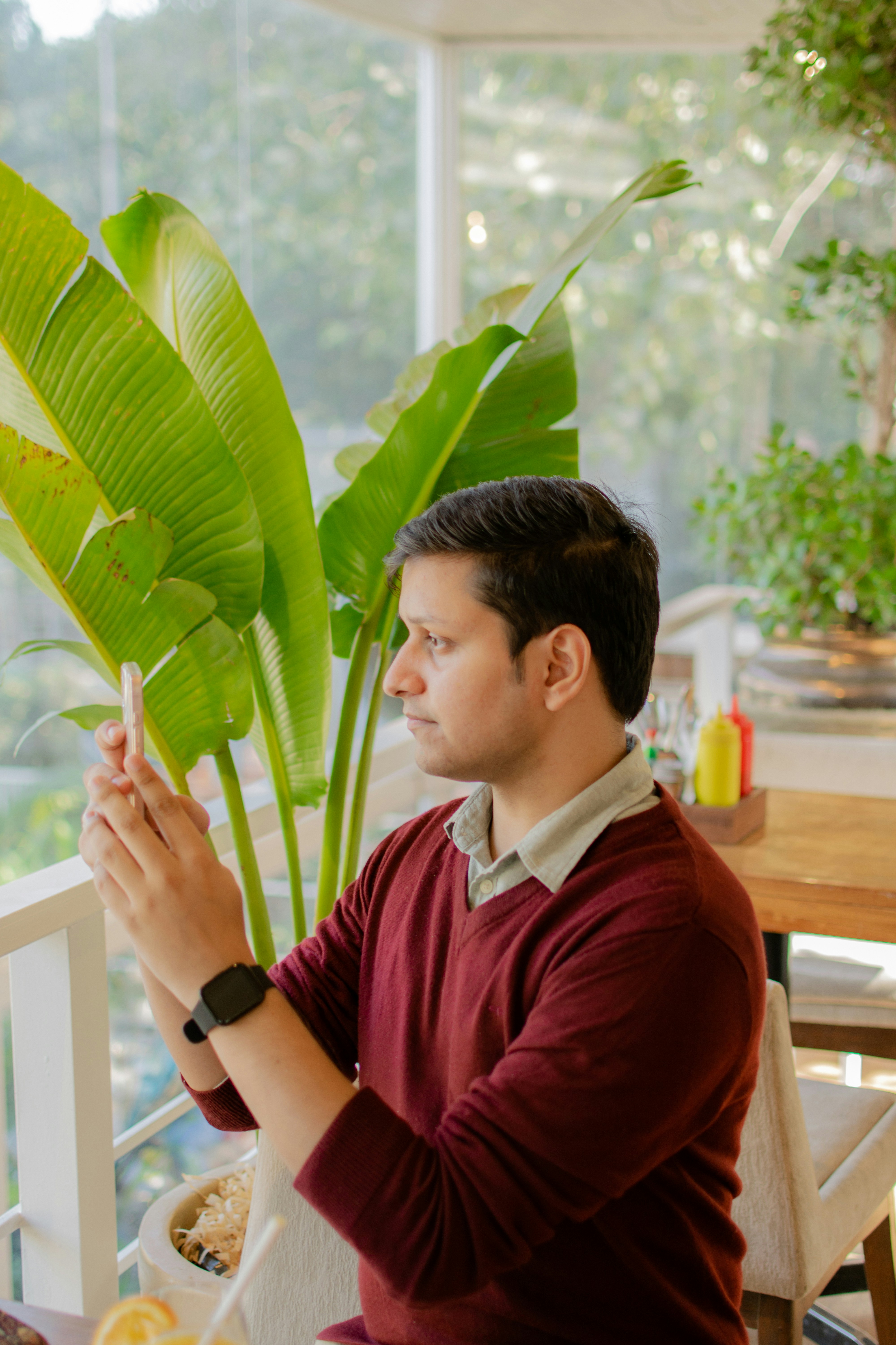 a man sitting at a table with a plant in his hand