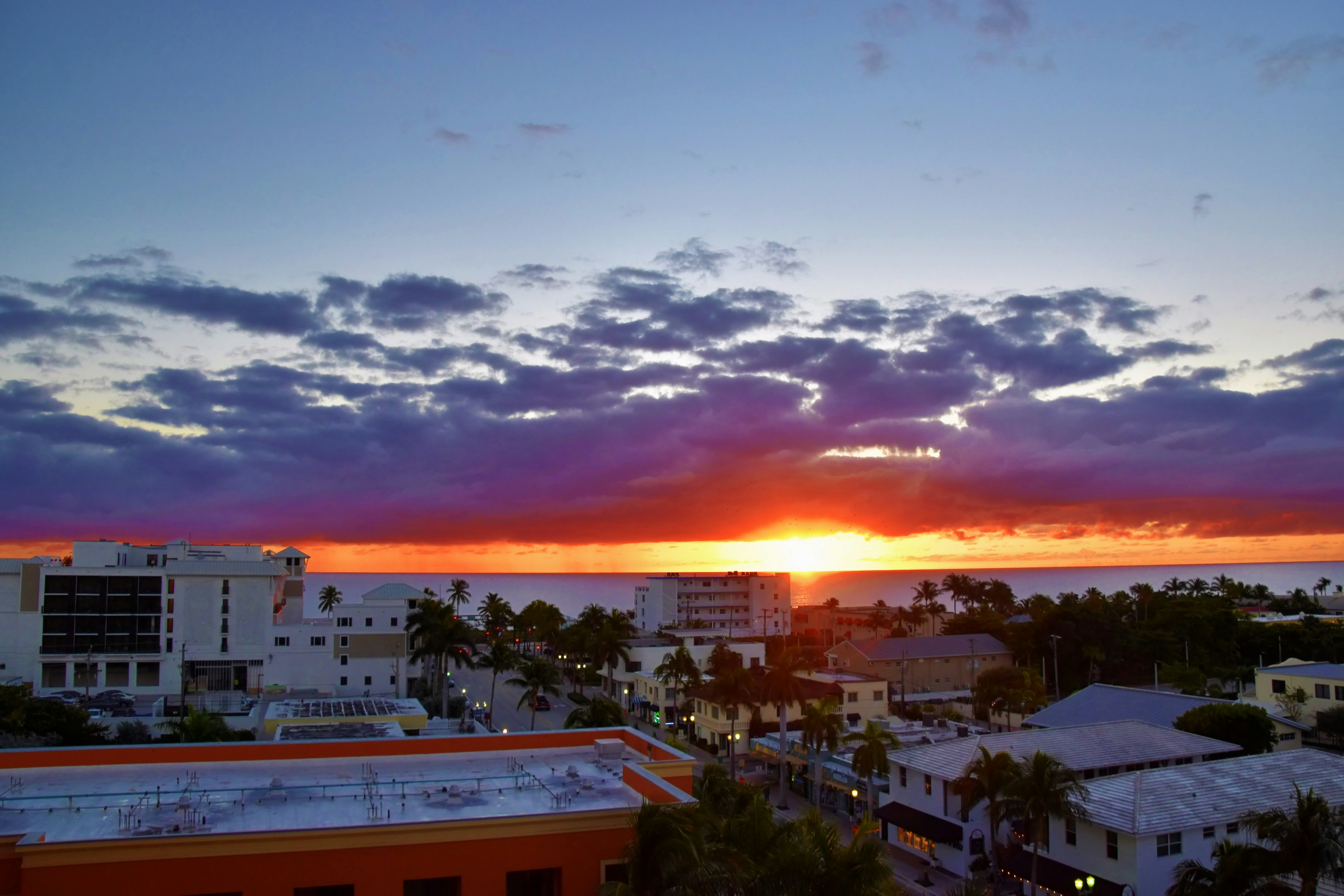 Foto El sol se está poniendo sobre una ciudad con palmeras – Imagen ...