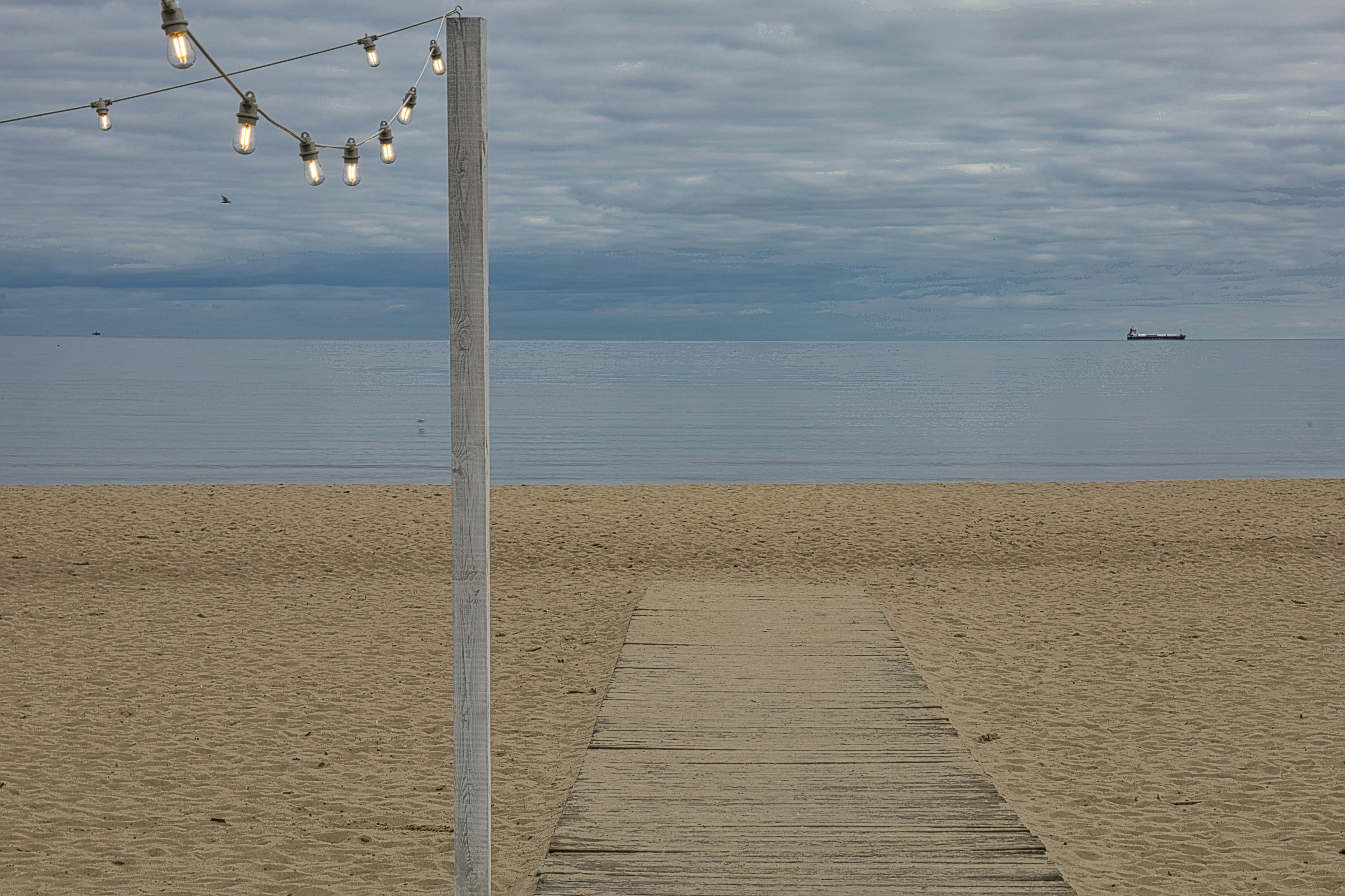 String-Lit Post Framing a Quiet Beach Path Toward the Horizon