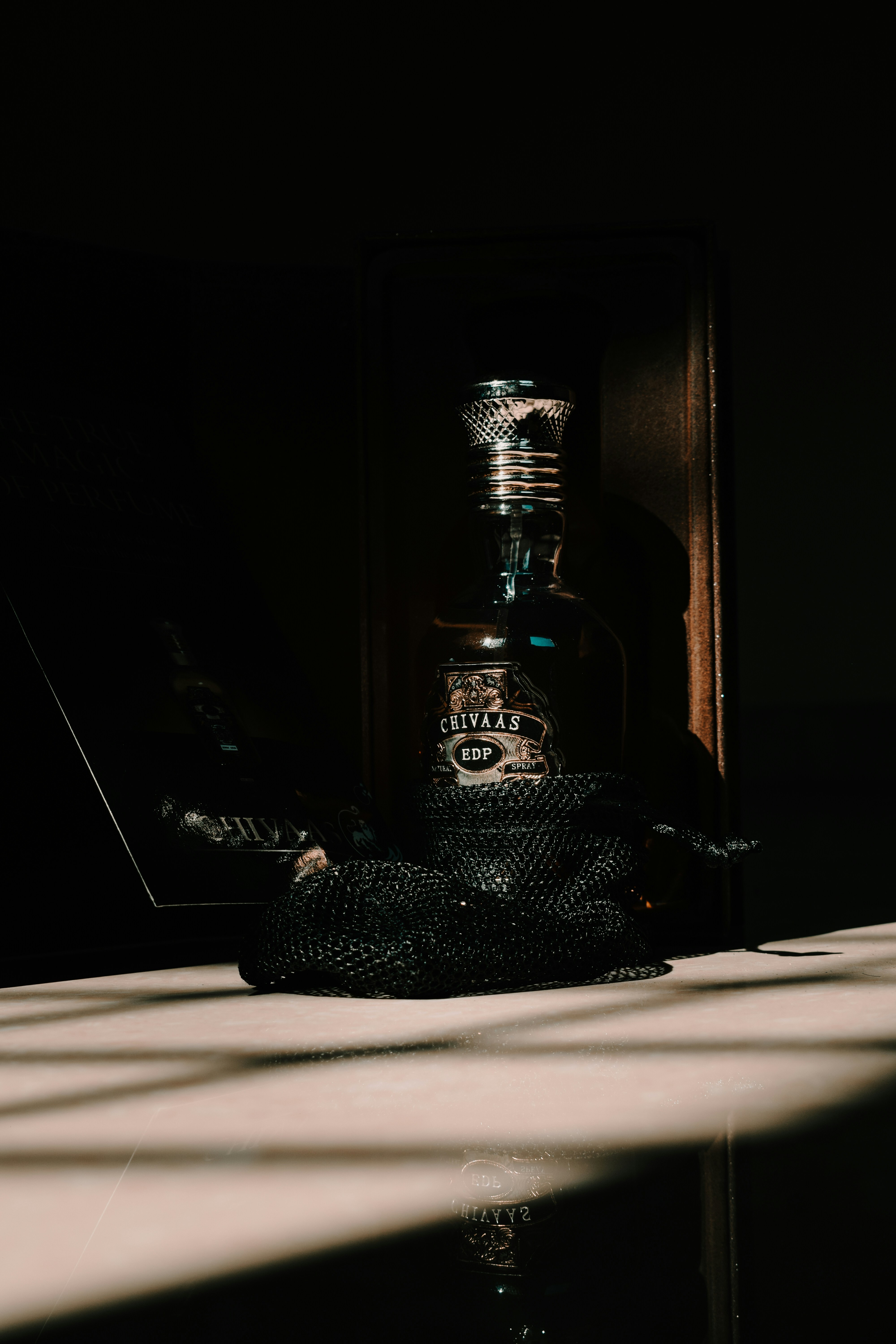 Chivas in the Shadow Box: A Whisky Bottle Emerges Under a Narrow Spotlight