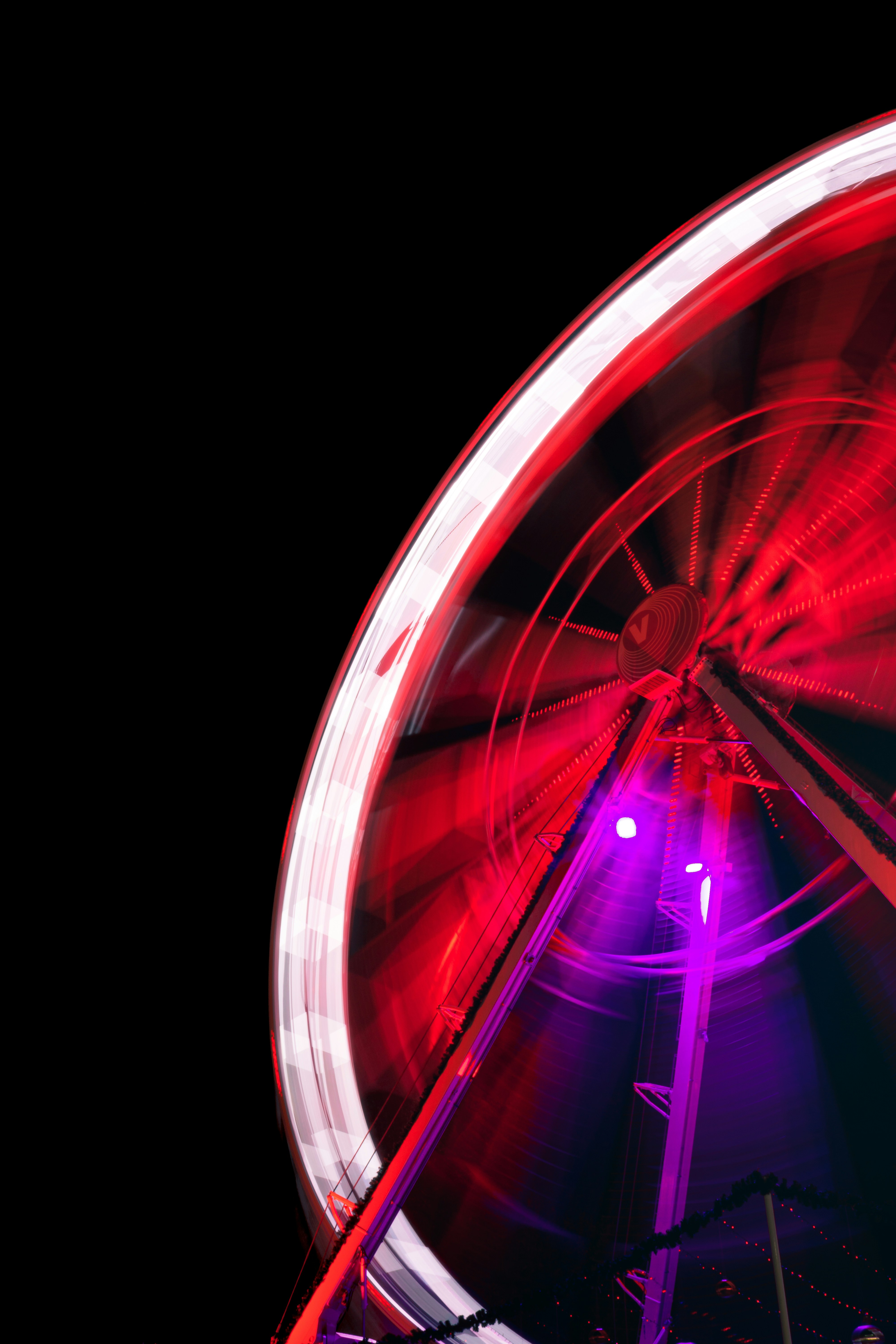 Neon Spokes in Motion: A Red-Purple Ferris Wheel at Night