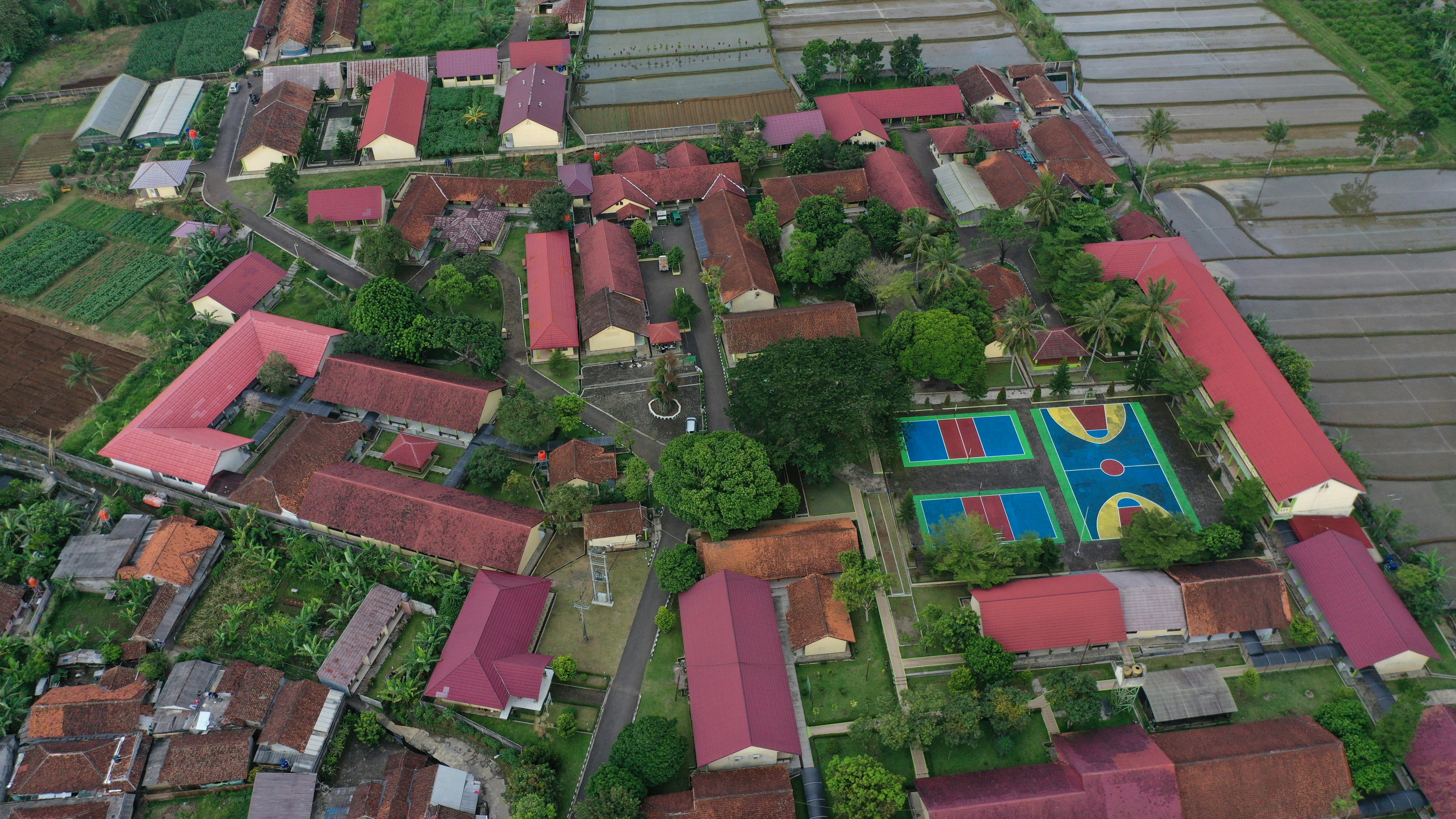 Aerial view of the entire school buildings (offices, classrooms, laboratories, bakery, cow pens, chicken coops, fish ponds, futsal pitch, basketball court, volleyball courts, school's mosque, school's main office)
