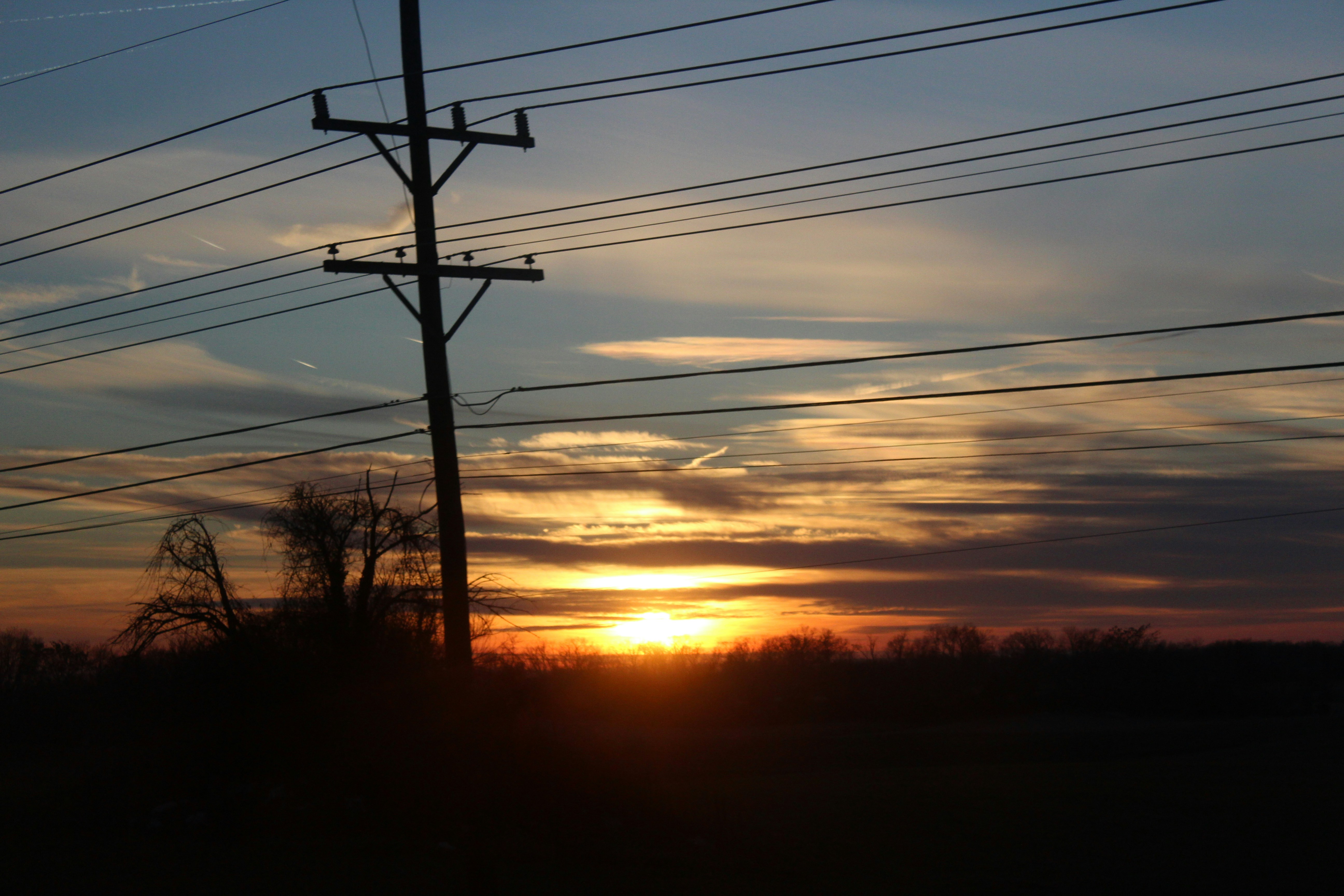 The sun is setting behind power lines and telephone poles photo – Free ...