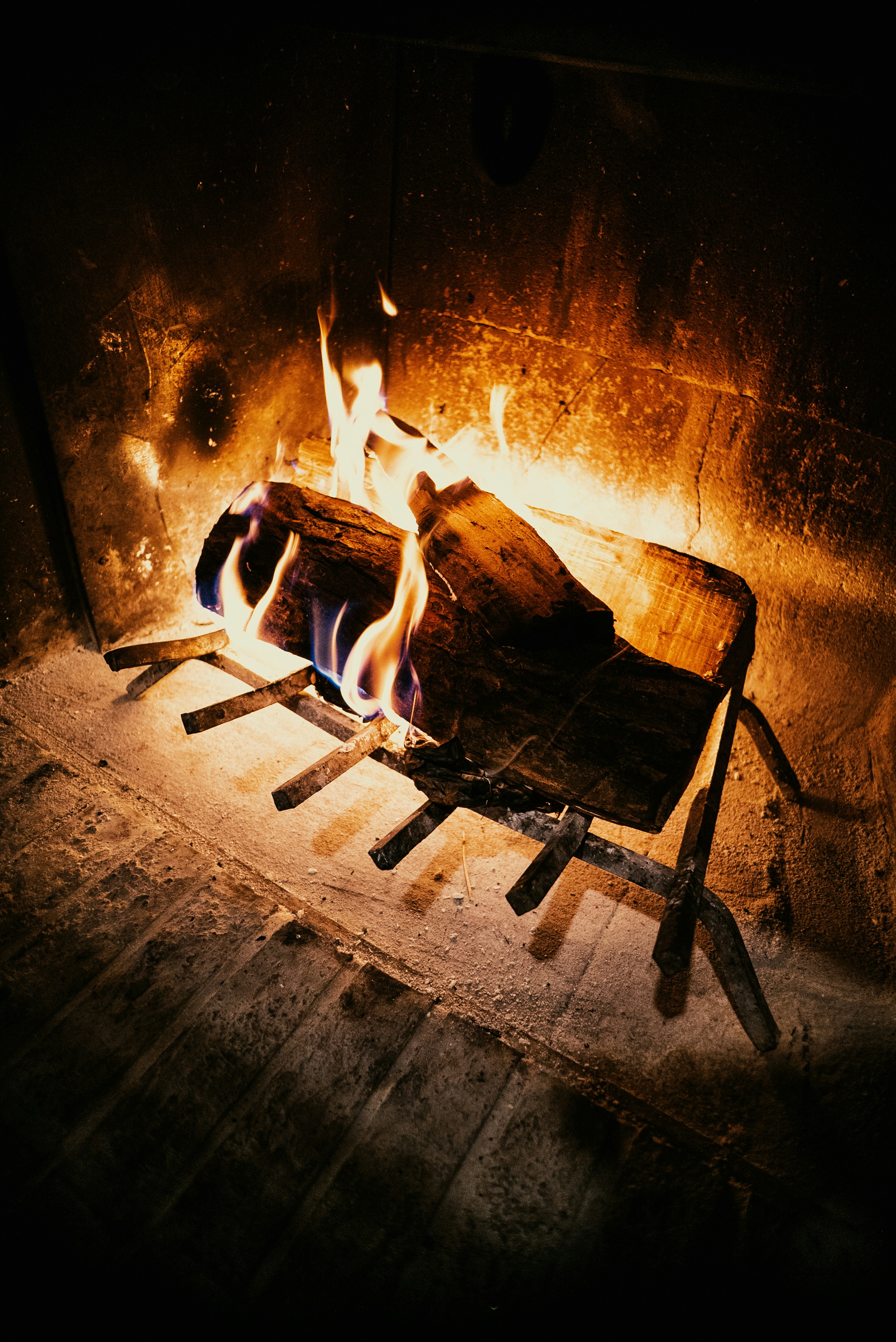 A fire burning in a fireplace with a wooden bench photo – Free ...