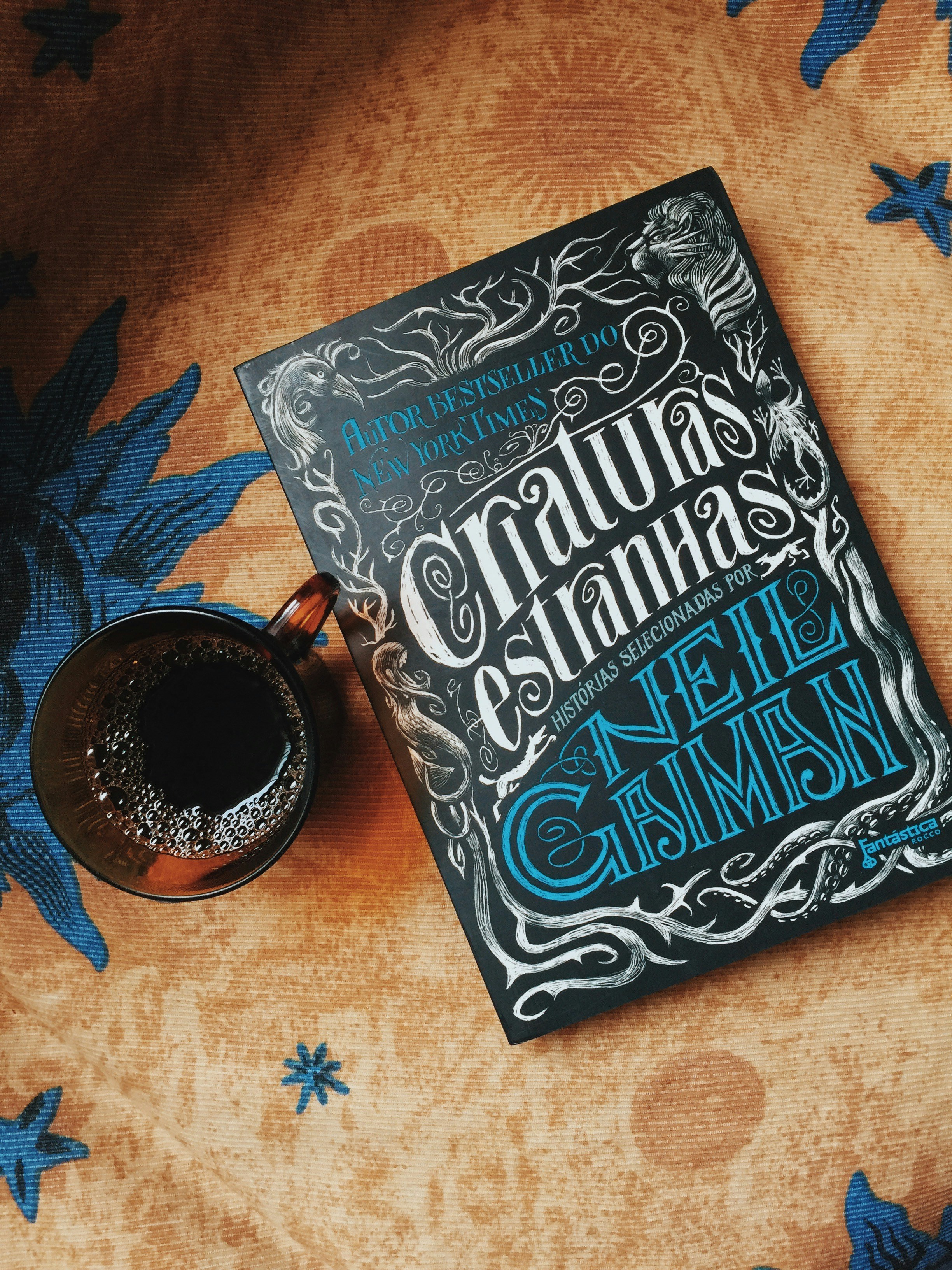 Ornate Noir: A Turquoise-Typed Hardcover Resting by Coffee on an Amber Blanket