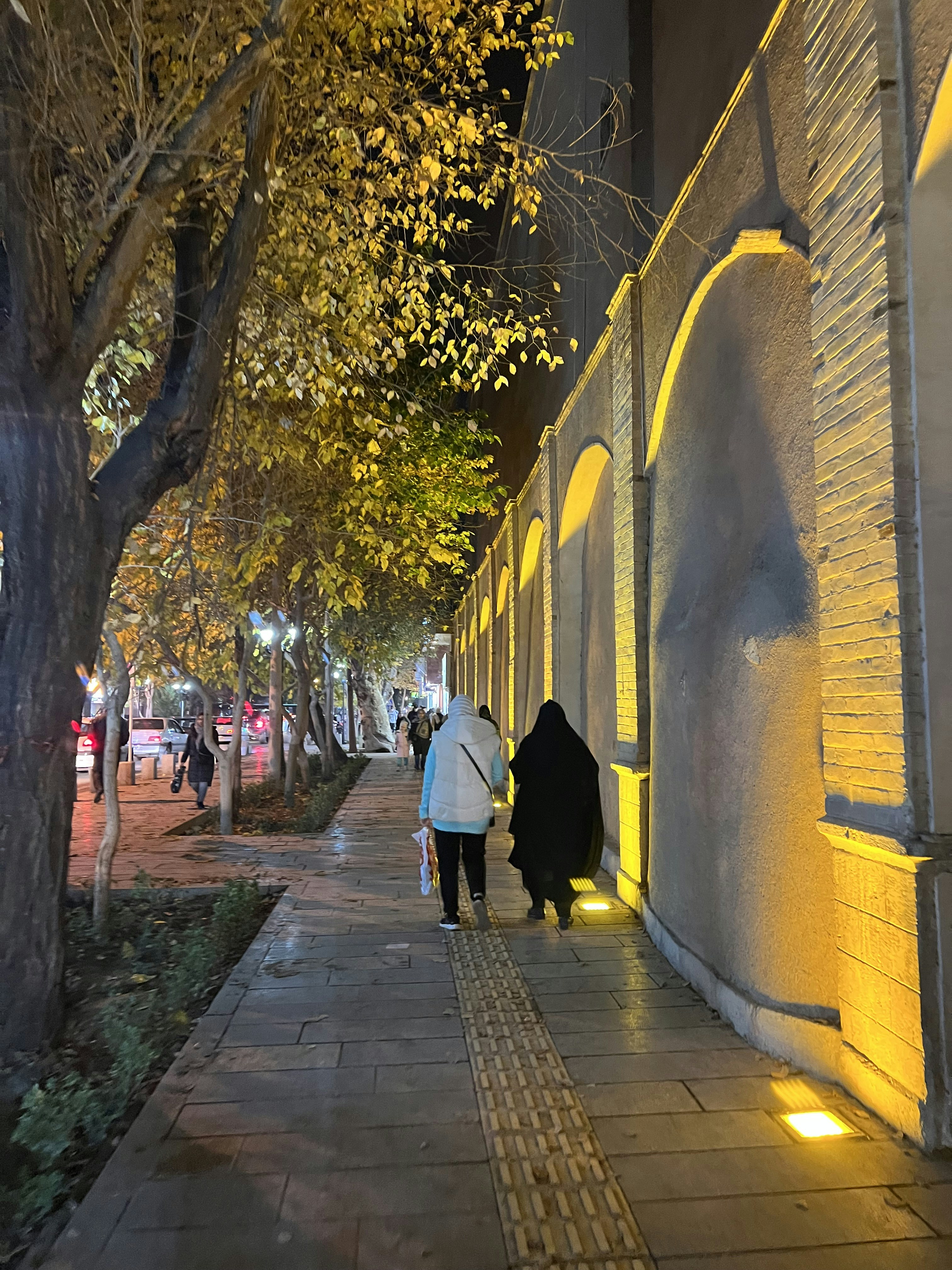 a couple of people walking down a sidewalk