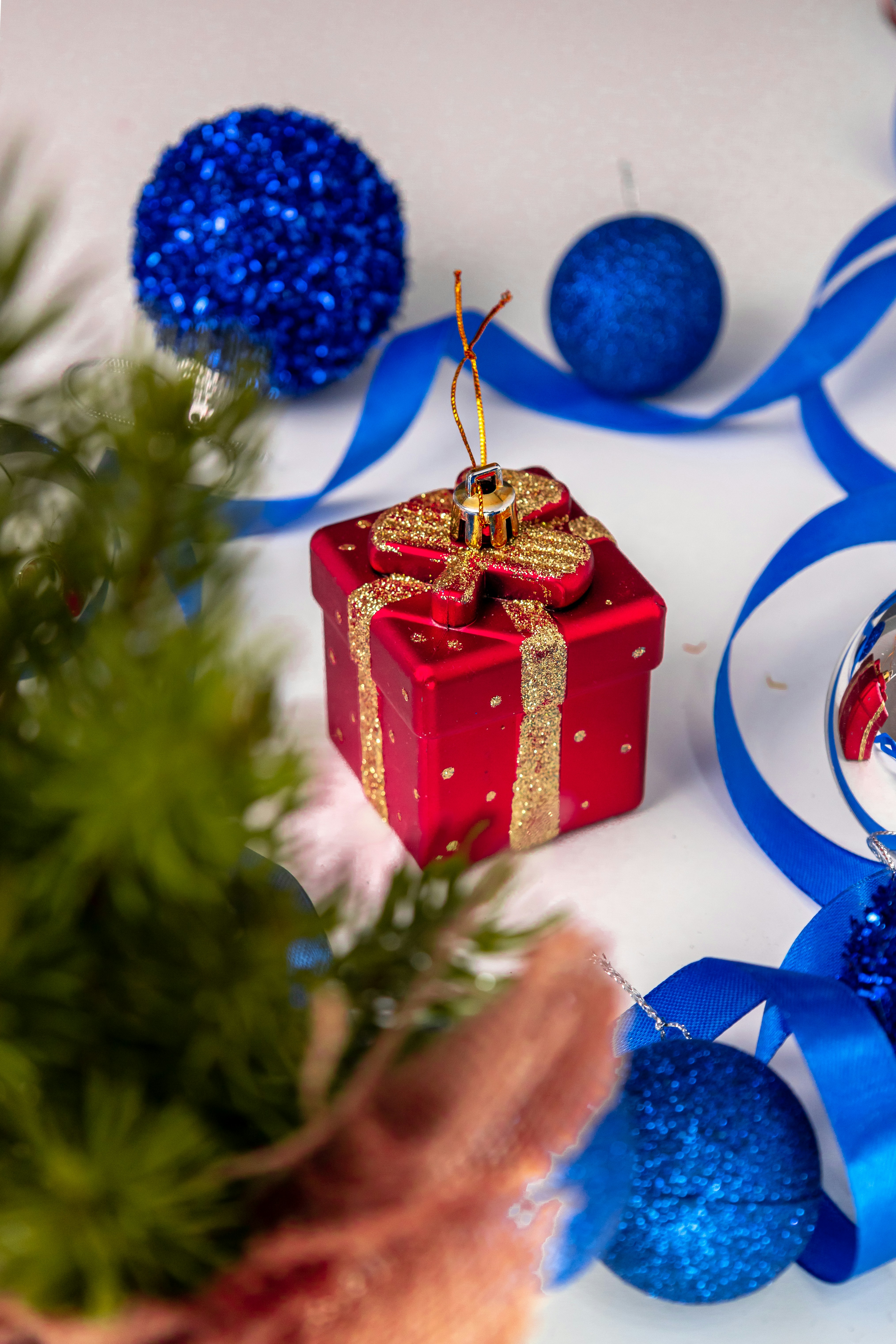 Crimson Gift Crowned by Glittering Gold Ribbon Among Blue Ornaments