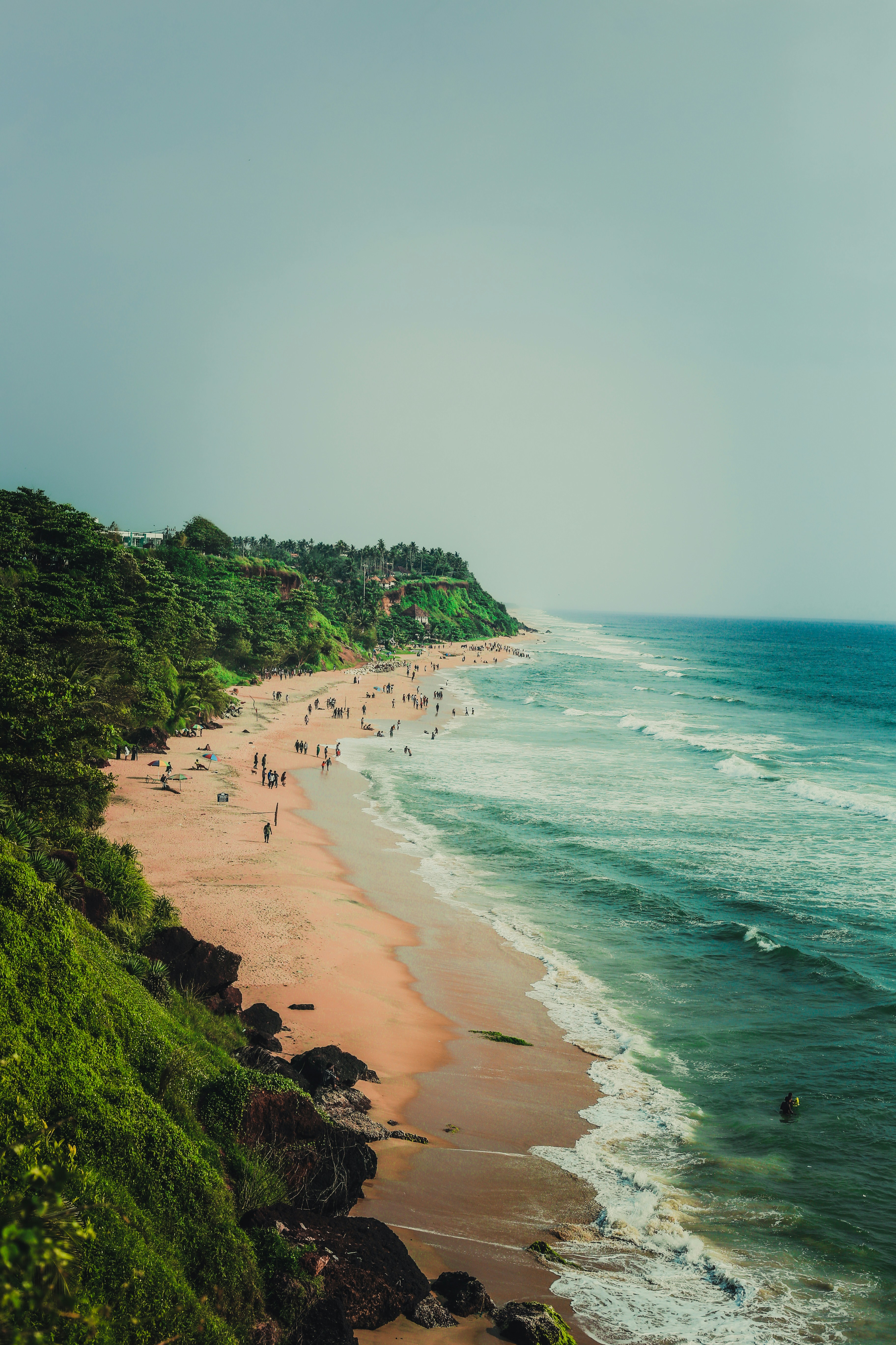 Un grupo de personas de pie en la cima de una playa junto al océano ...