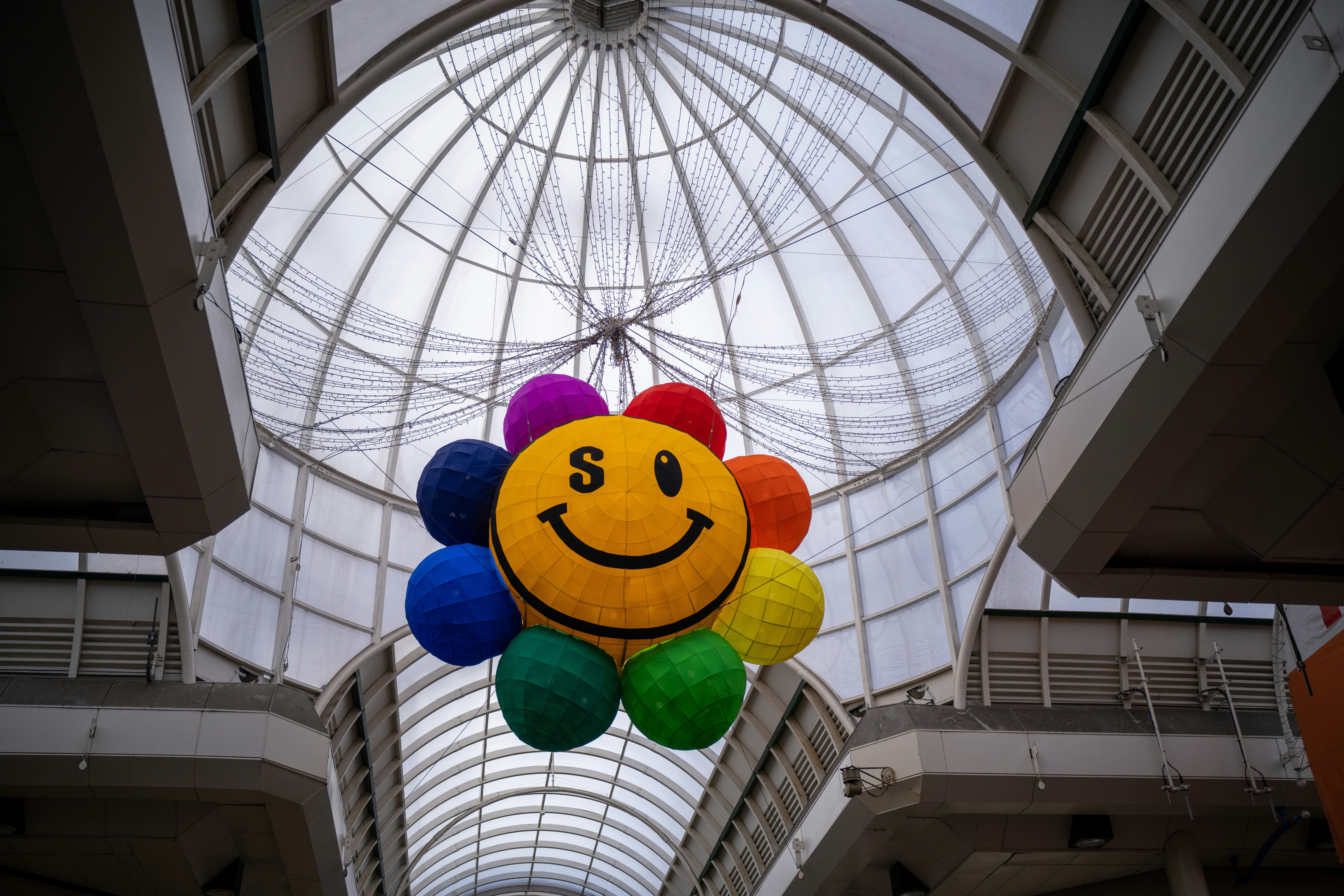 A smiley face balloon hanging from the ceiling of a building photo ...