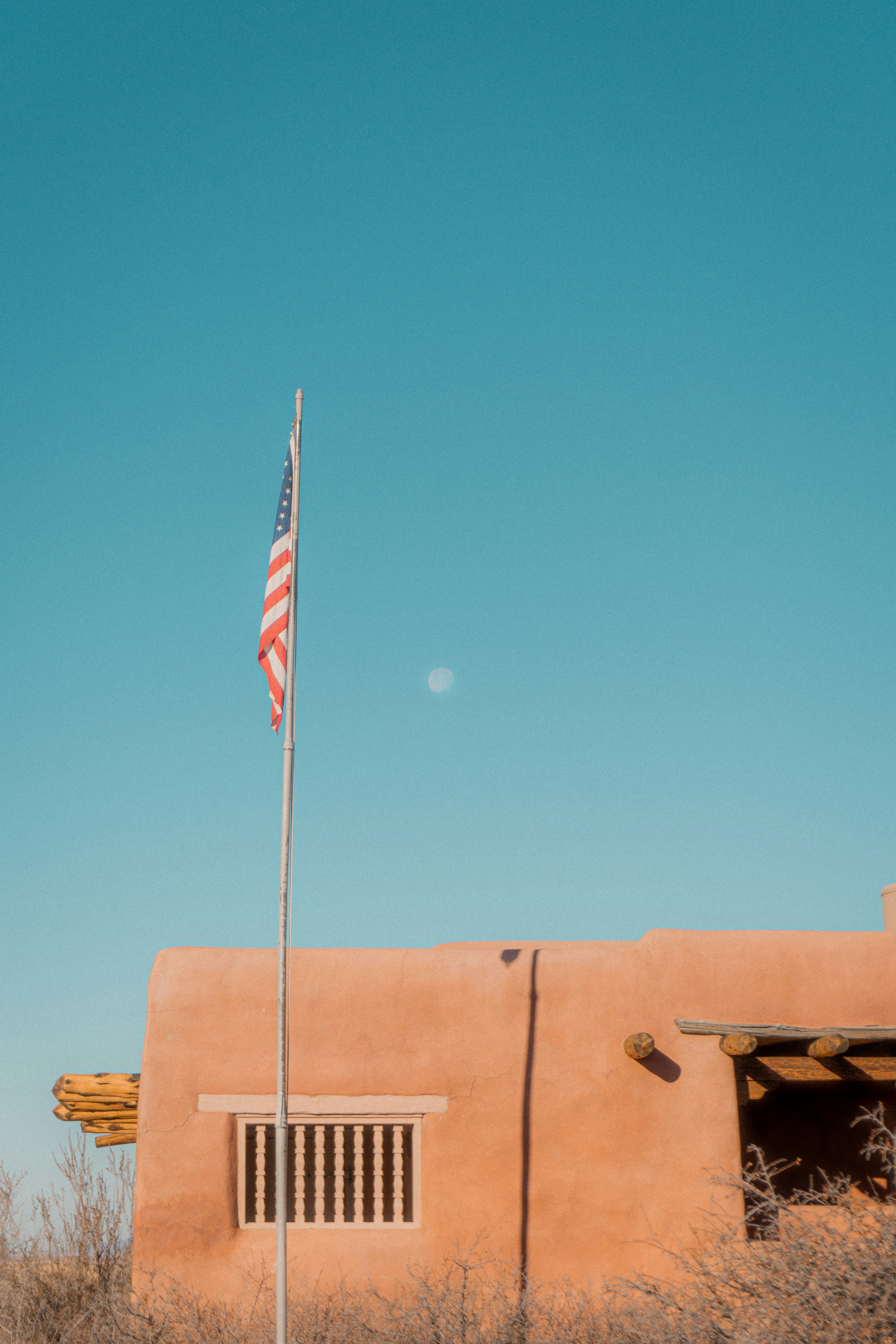 Flagpole and Adobe: A Quiet Southwest Moment Under Cerulean Sky