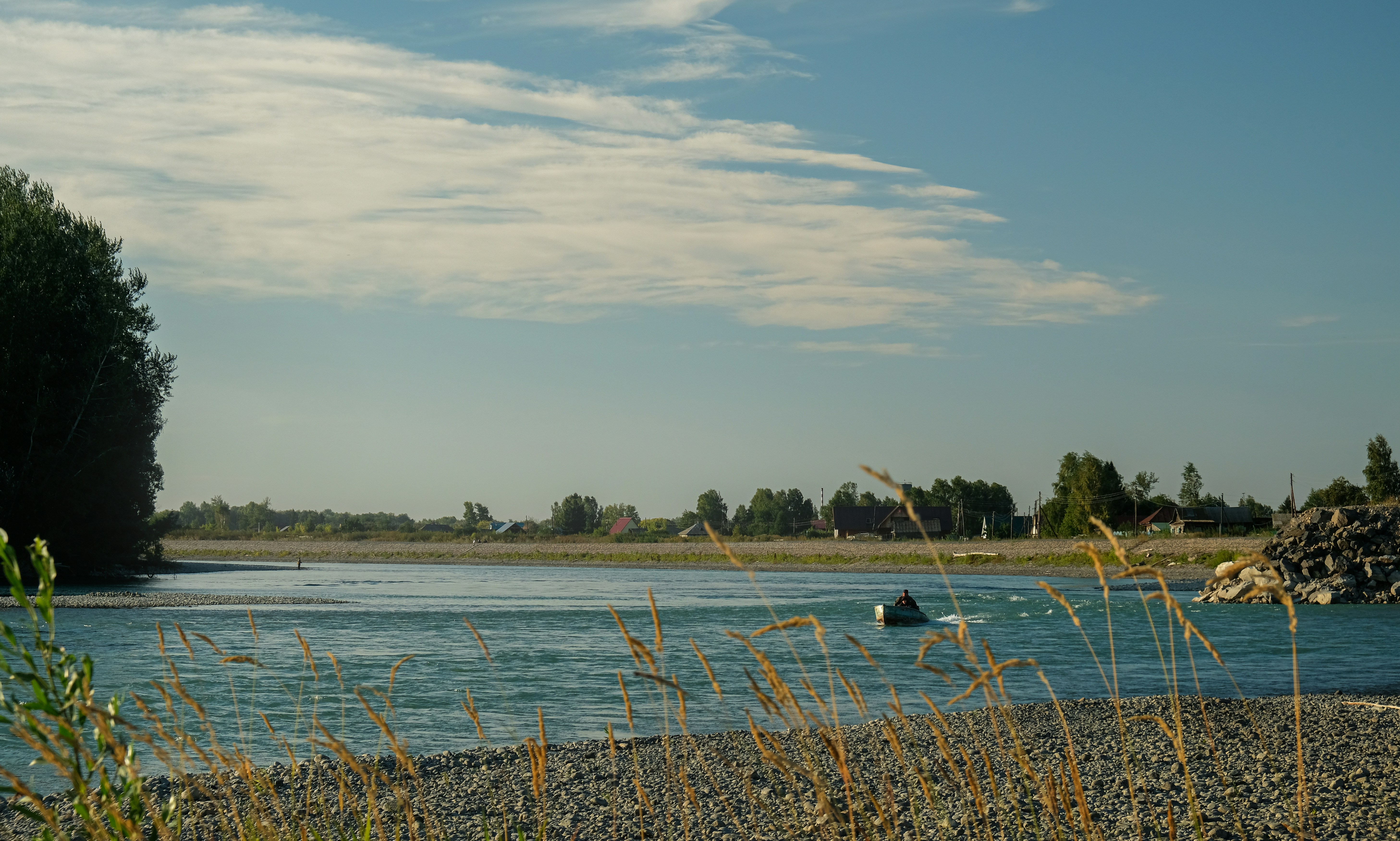 Solitary Boat Drifts Along a Pebble Riverbank