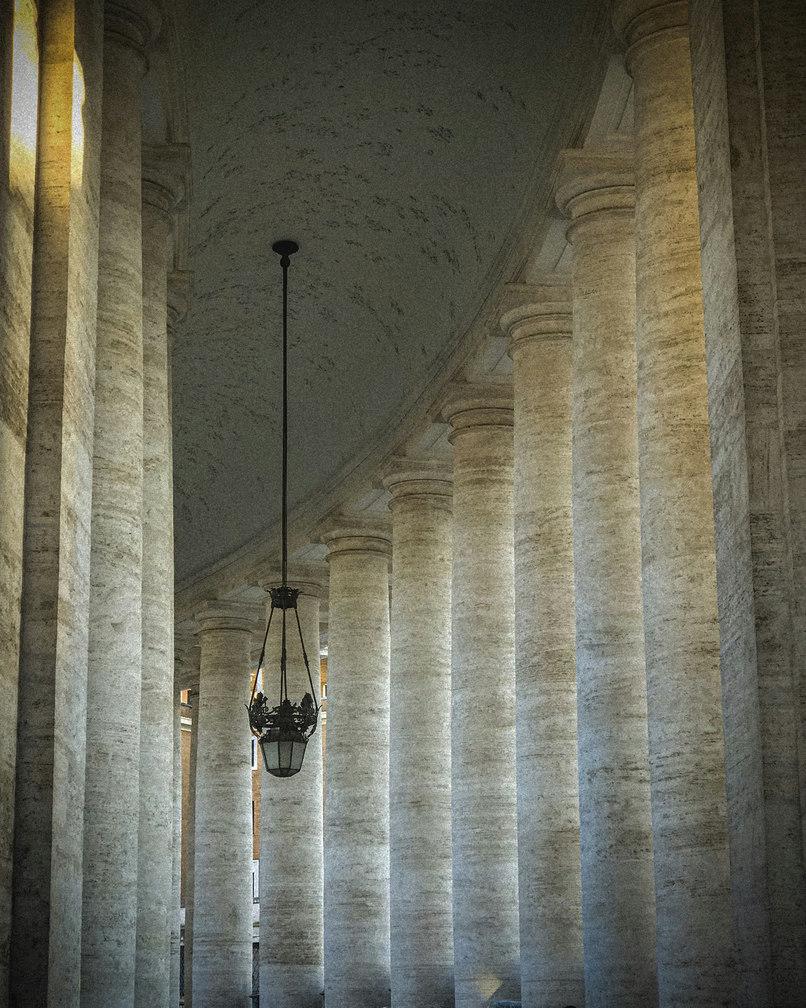 A room with columns and a chandelier hanging from the ceiling photo ...