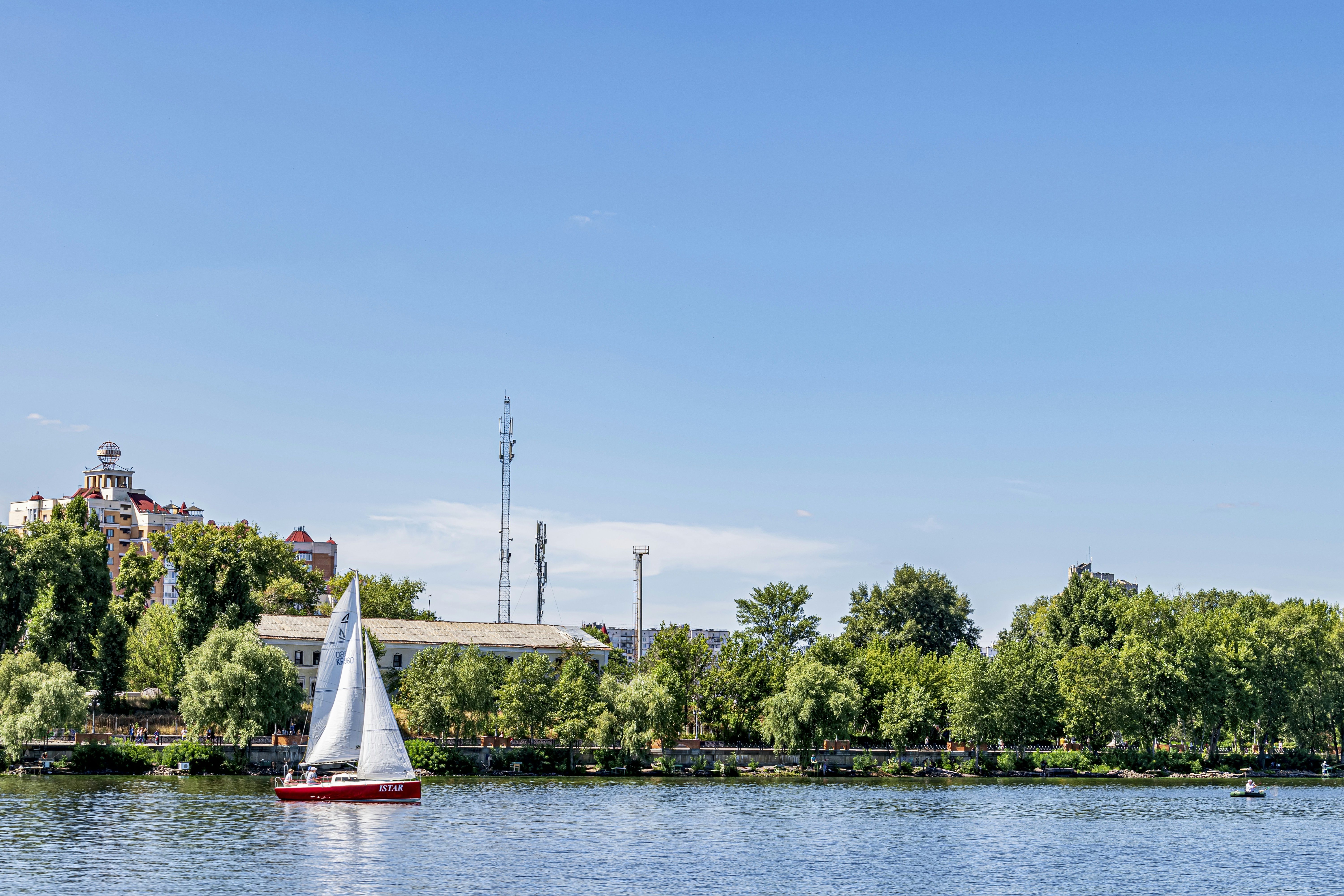 Sailboat on Tranquil River Under a Clear Blue Sky