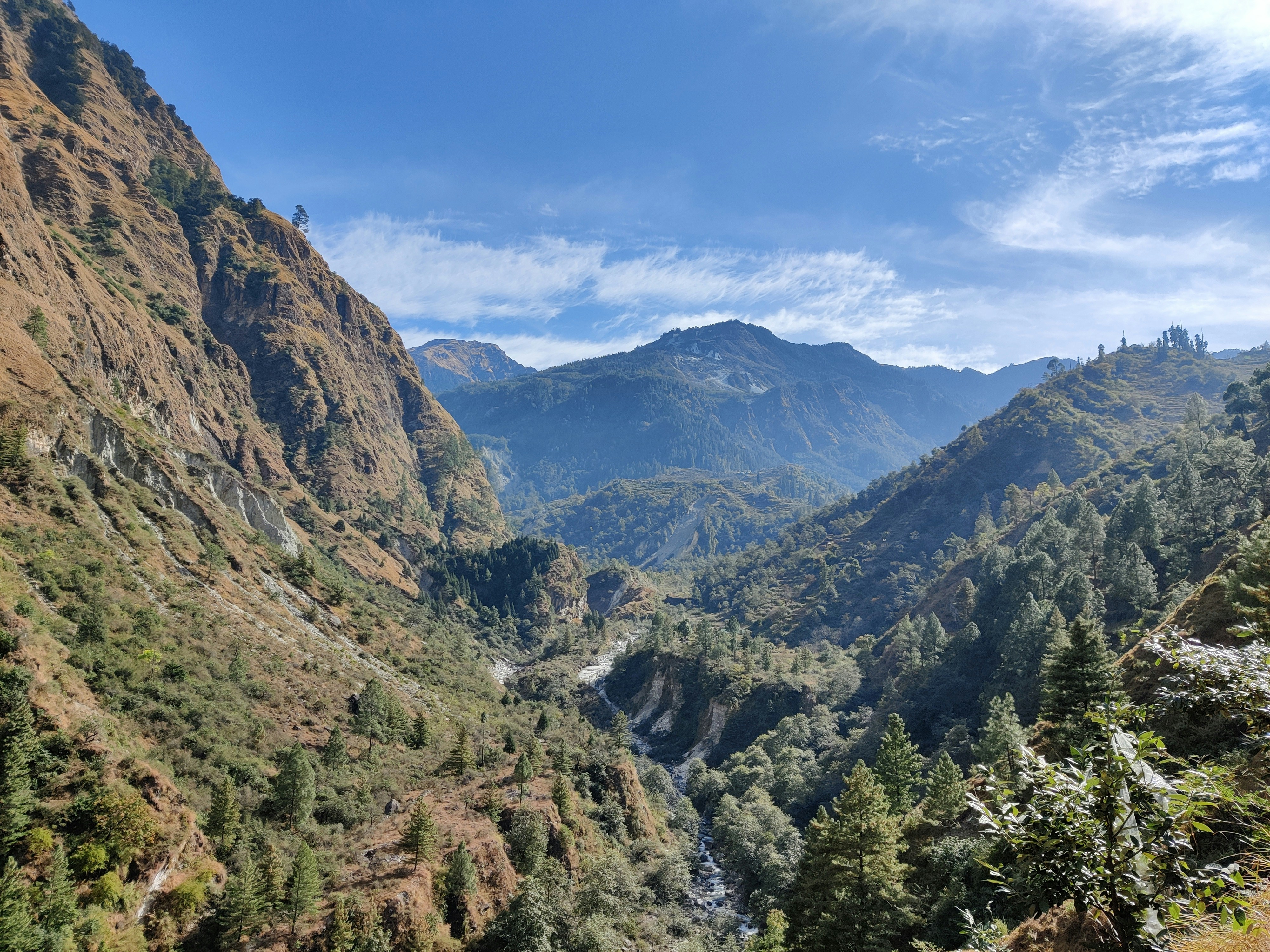 Expansive view of lush green valleys surrounded by rugged mountains under a clear blue sky.