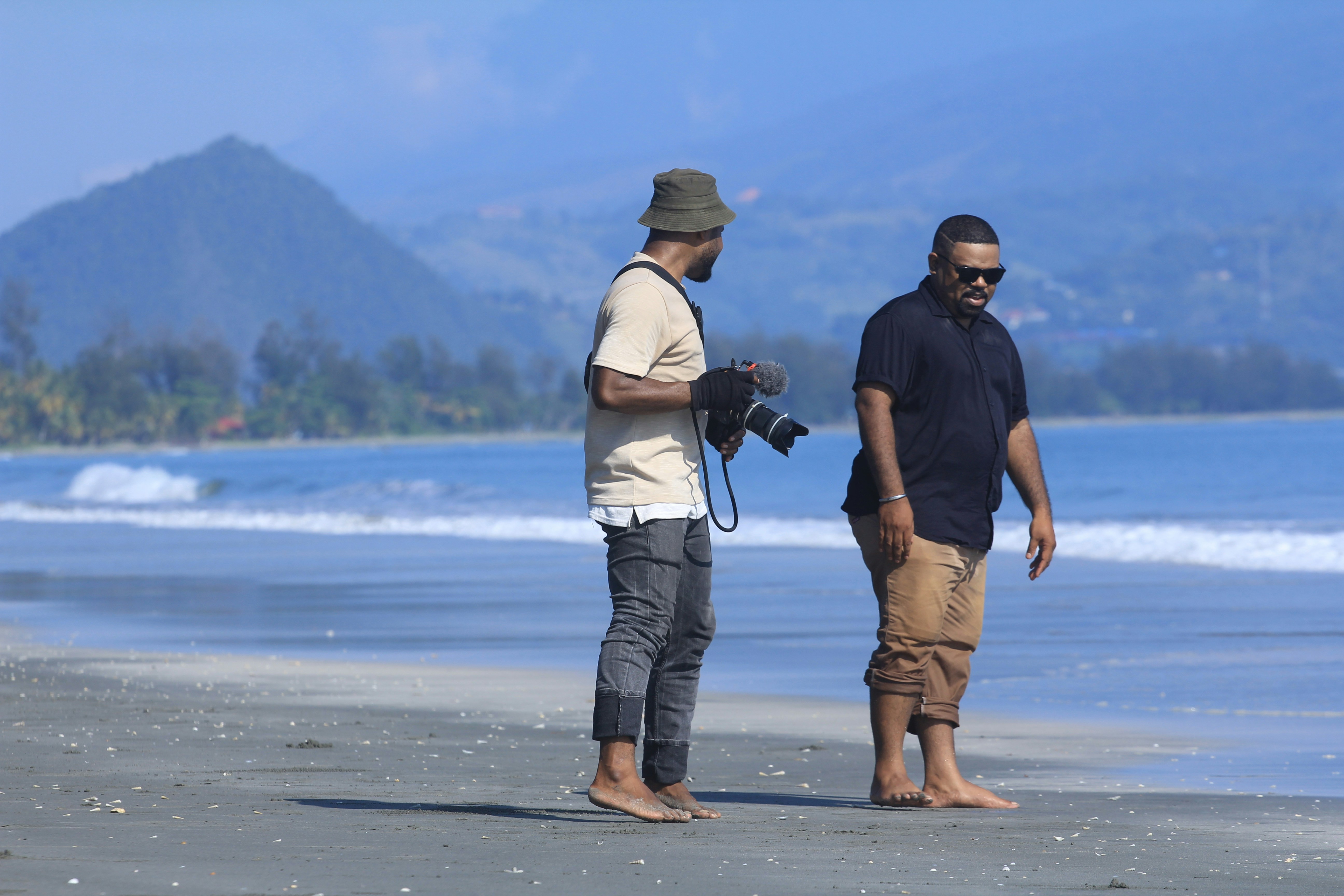 Two men standing on a beach with a camera photo – Free Man Image on ...