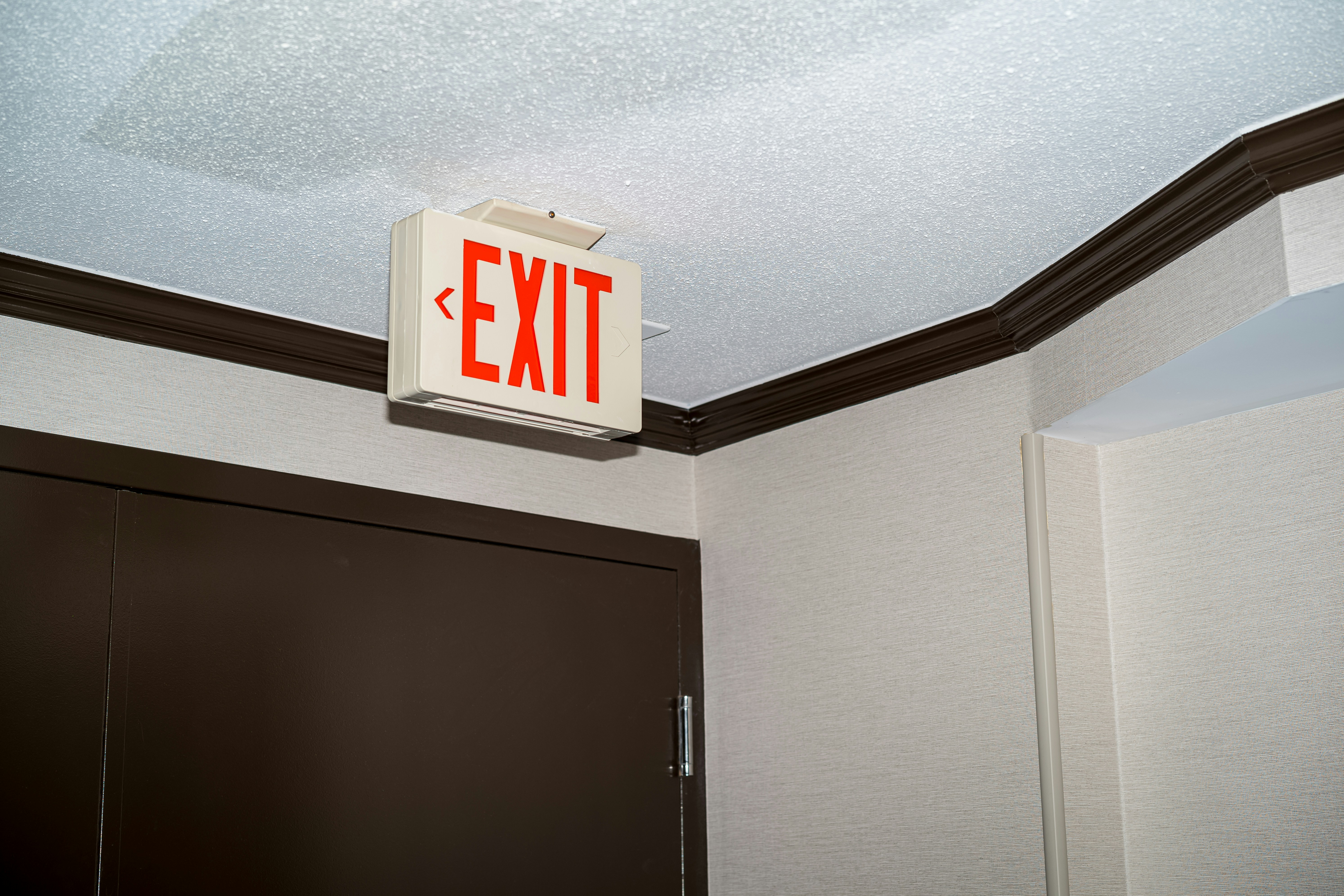 A red exit sign mounted to the ceiling of a bathroom photo – Free ...