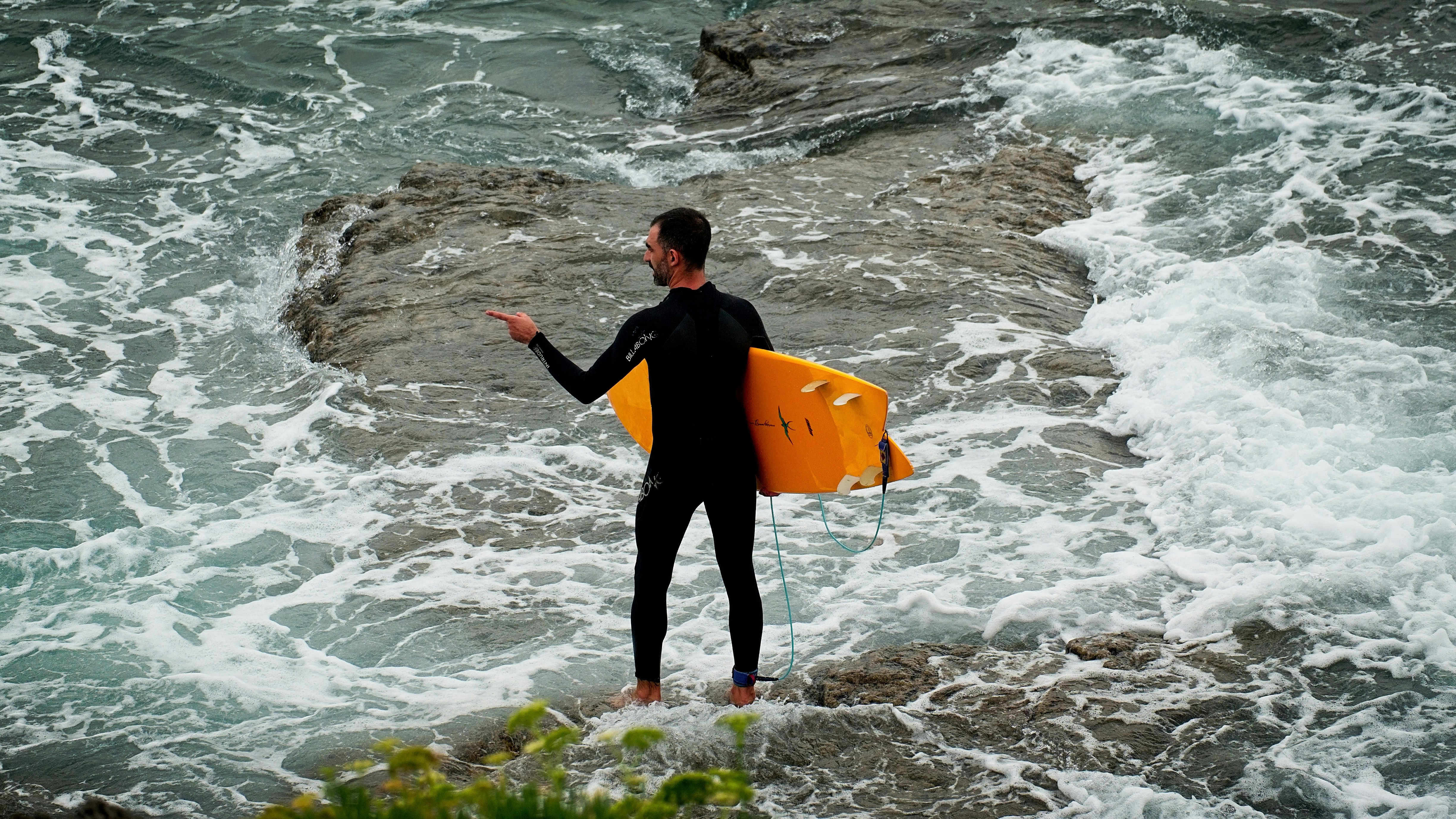 Un homme en combinaison de plongée tenant une planche de surf jaune ...