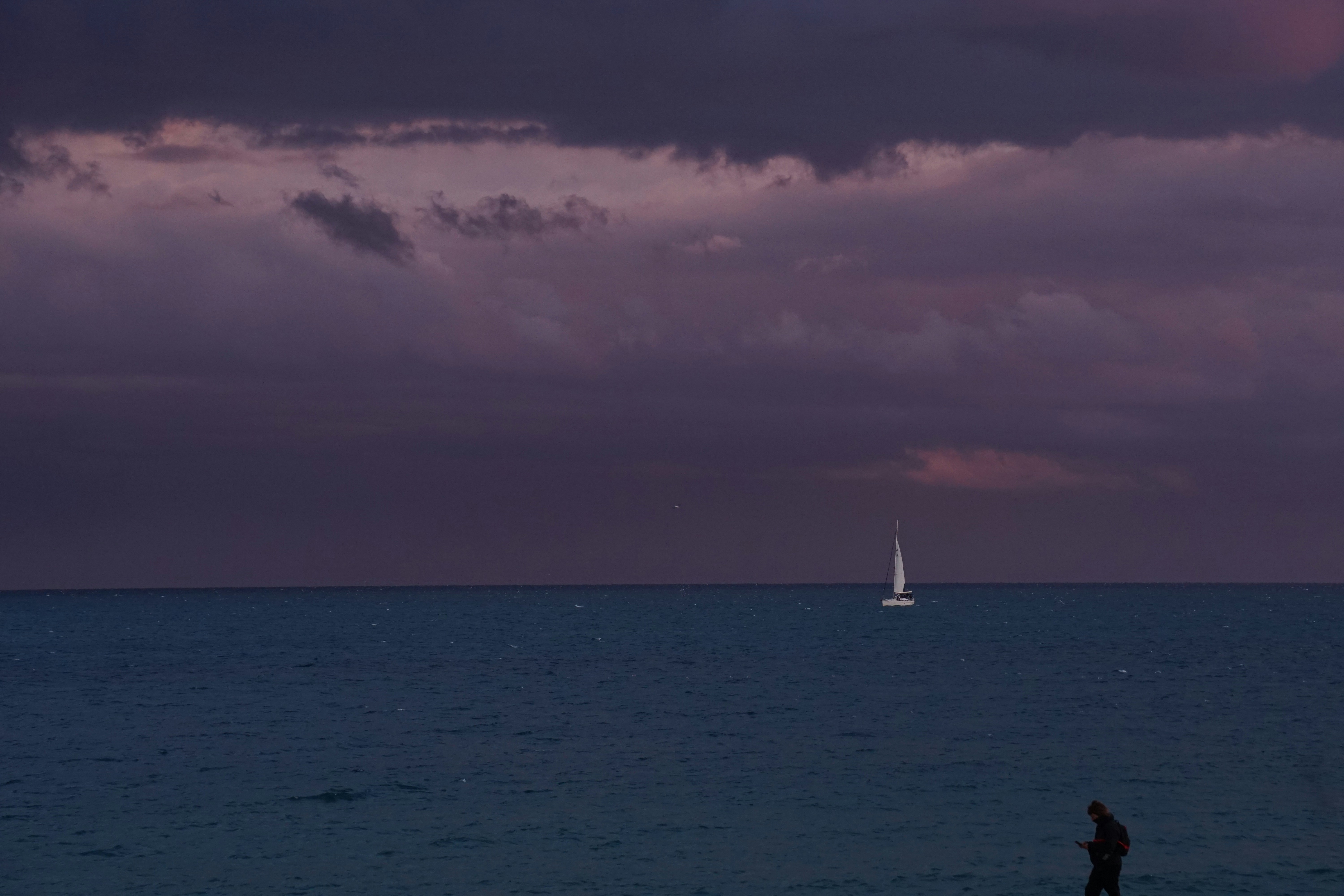 Dusk on the Quiet Sea: A Lone Sailboat Crossing a Violet Horizon