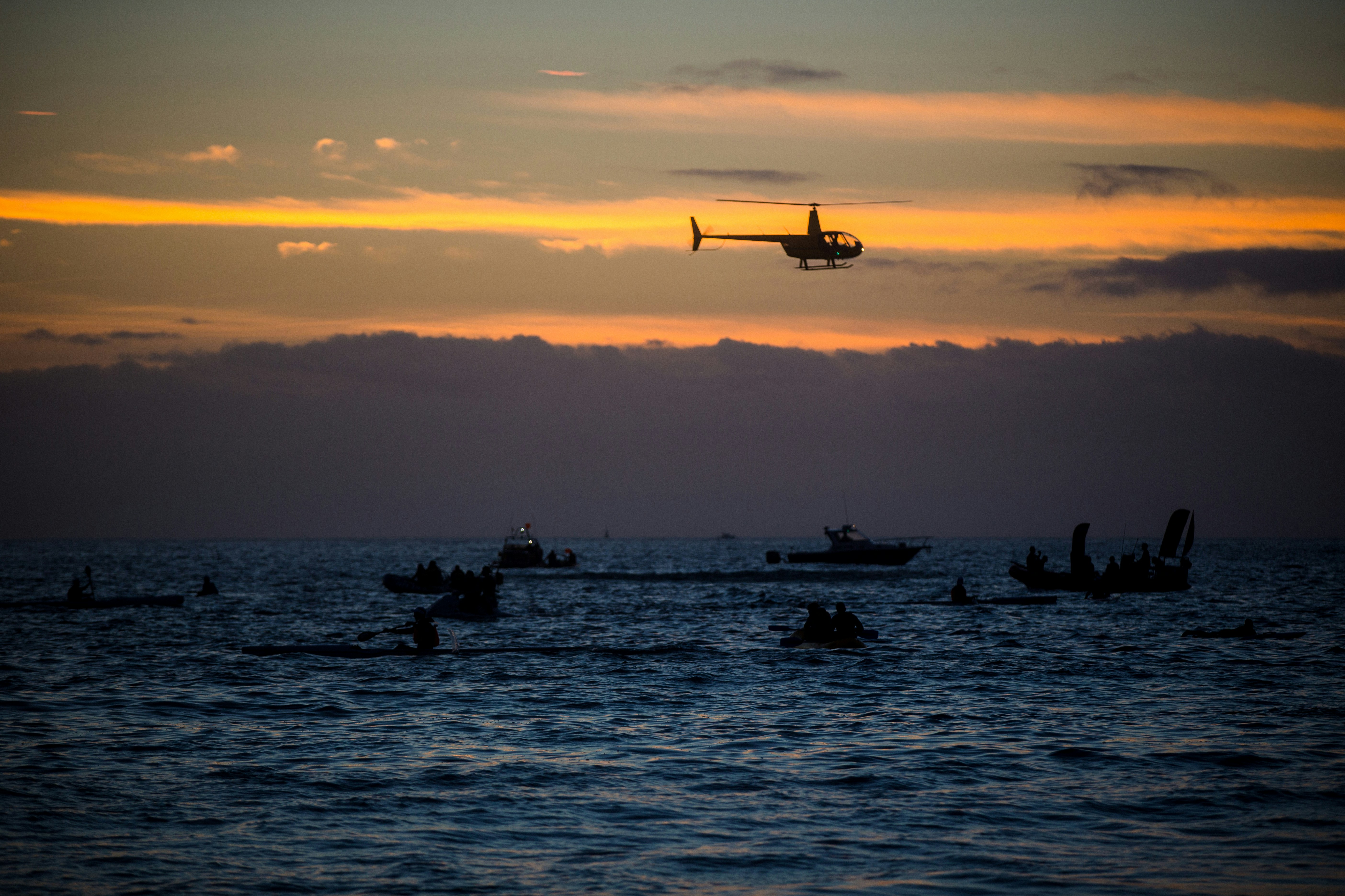 A helicopter flying over a group of boats in the ocean photo – Free ...