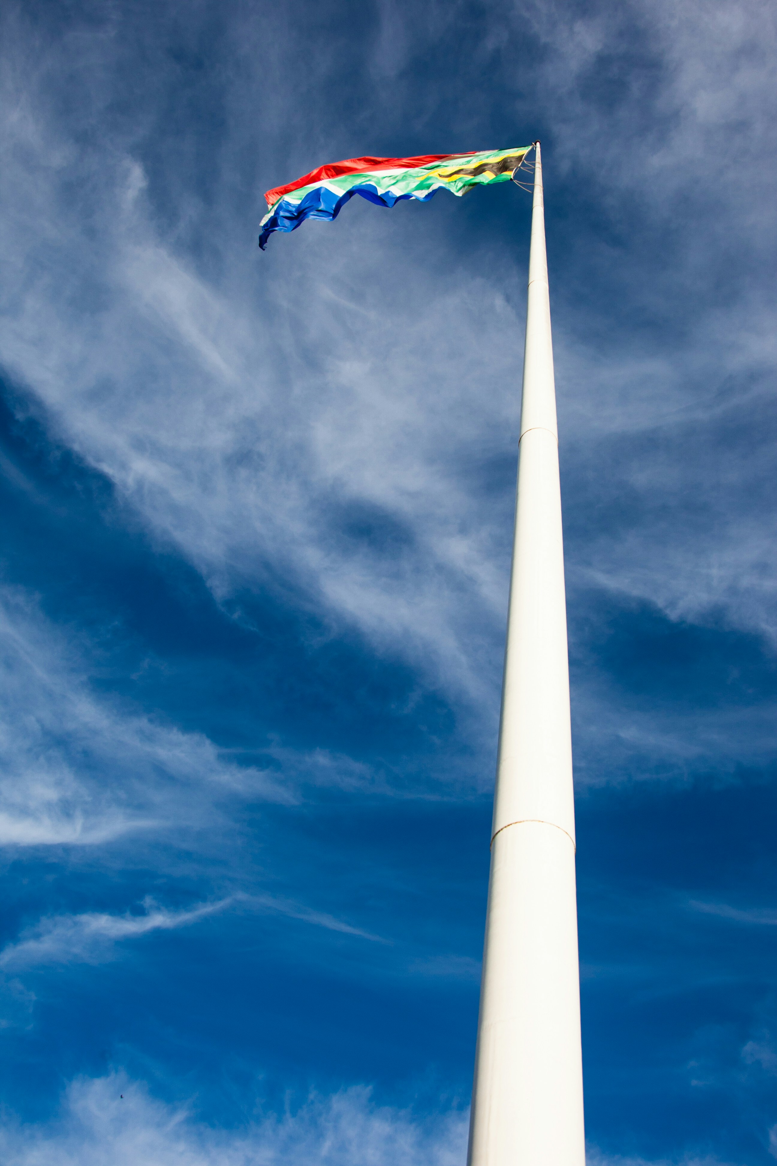 Foto zum Thema Eine hohe weiße Stange mit einer bunten Flagge darauf ...