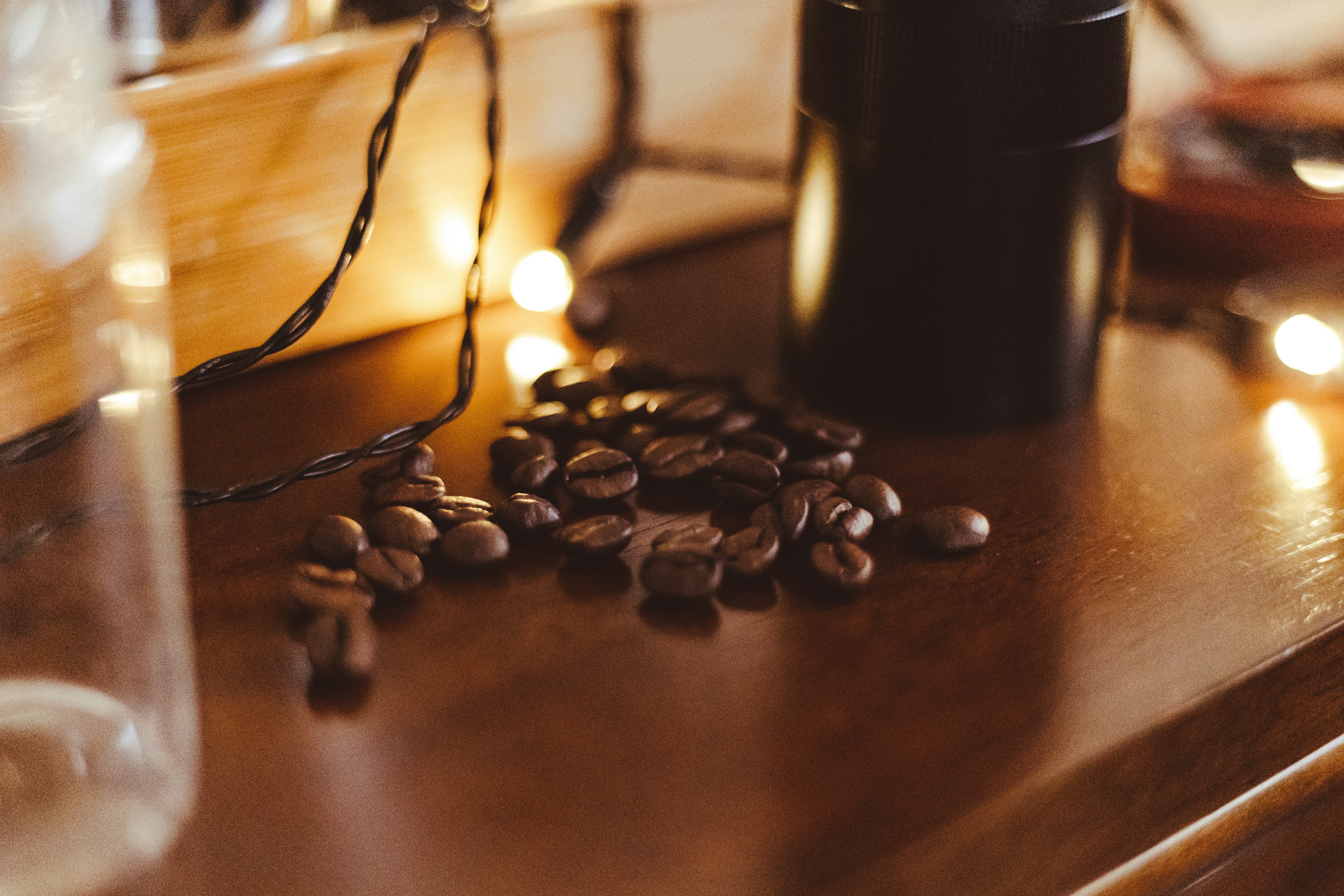 Amber Quiet: Coffee Beans Scatter Across a Wooden Bar Beneath Soft Fairy Lights