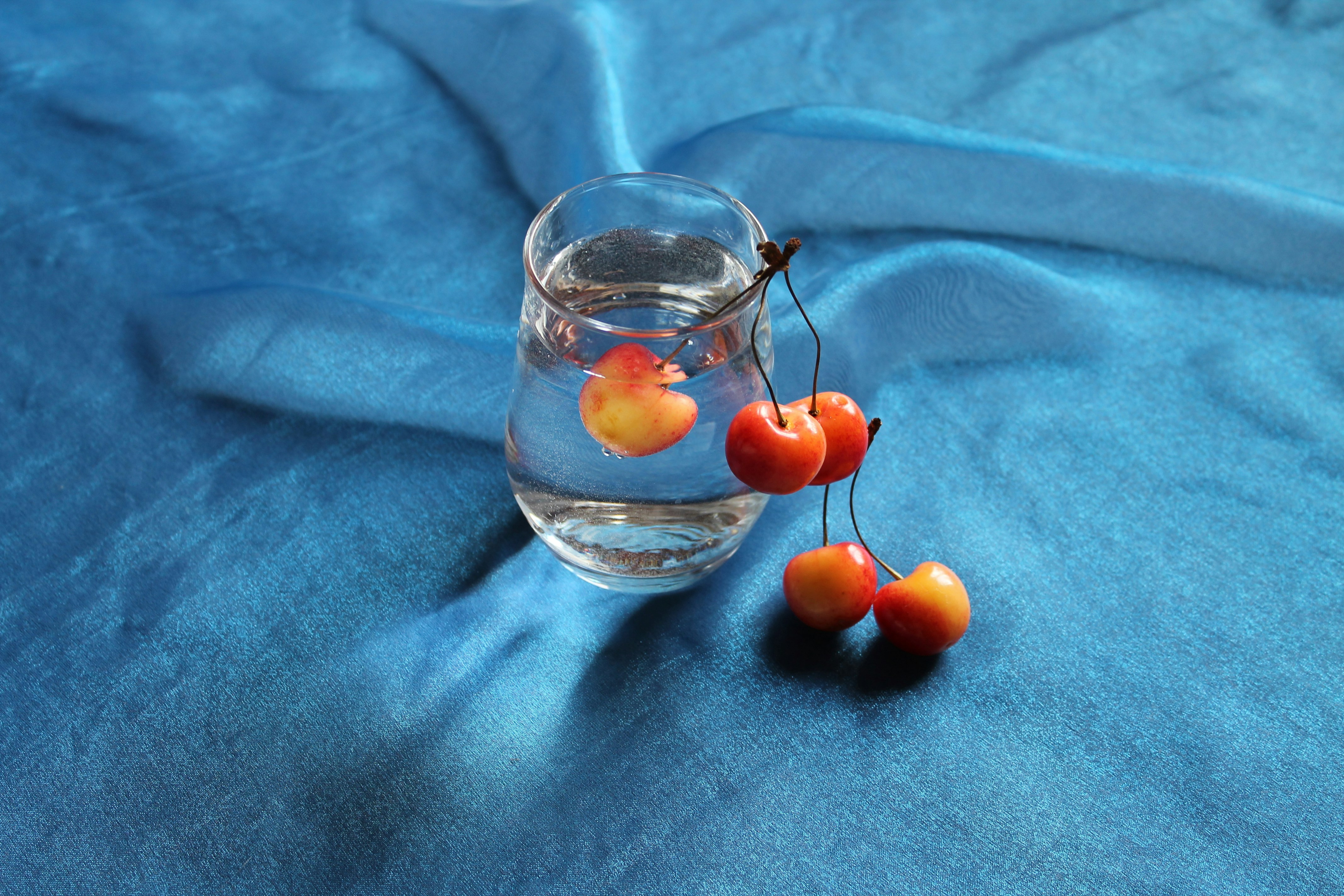 a glass of water with some cherries in it