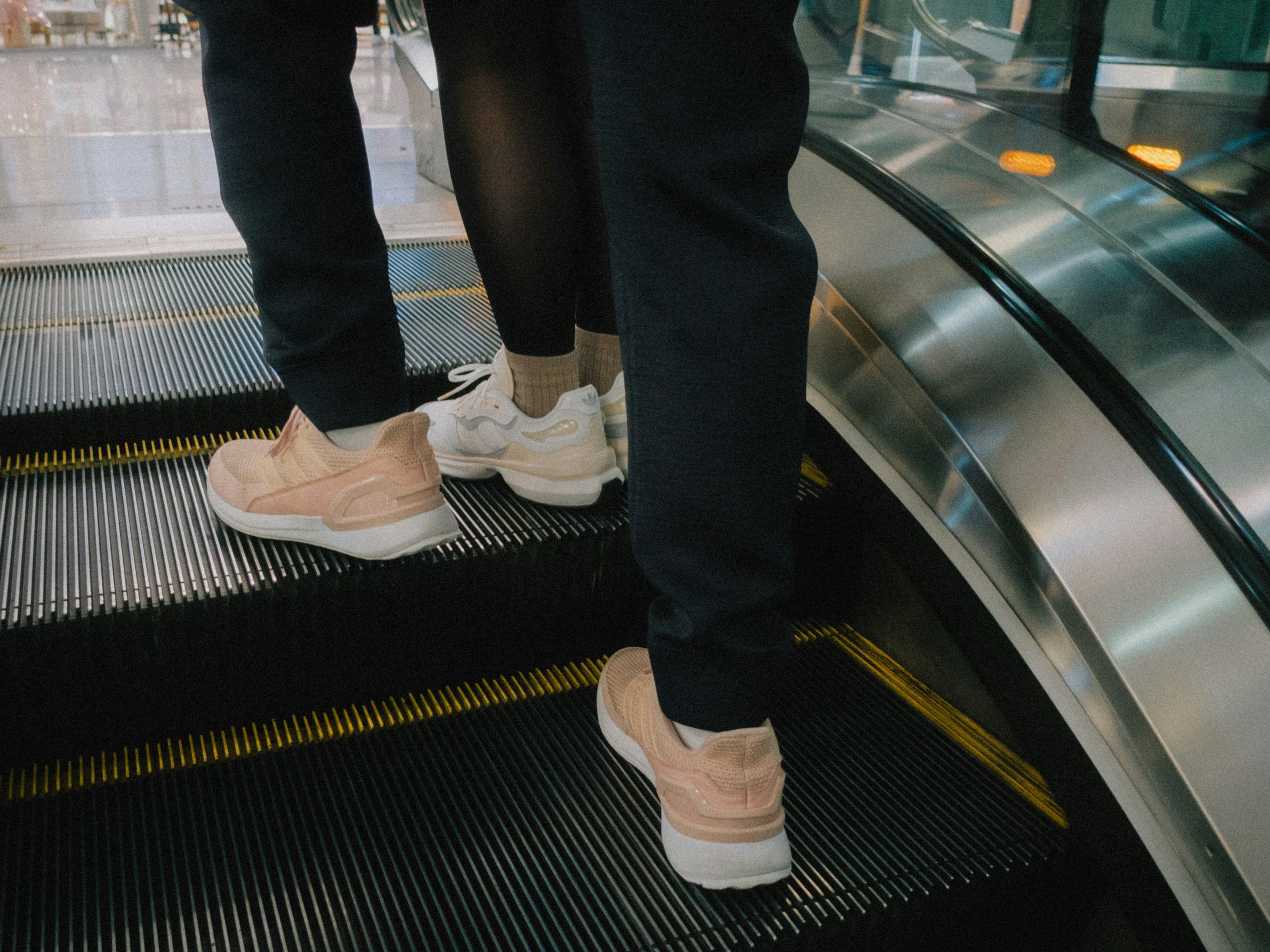 two people standing on an escalator in a building