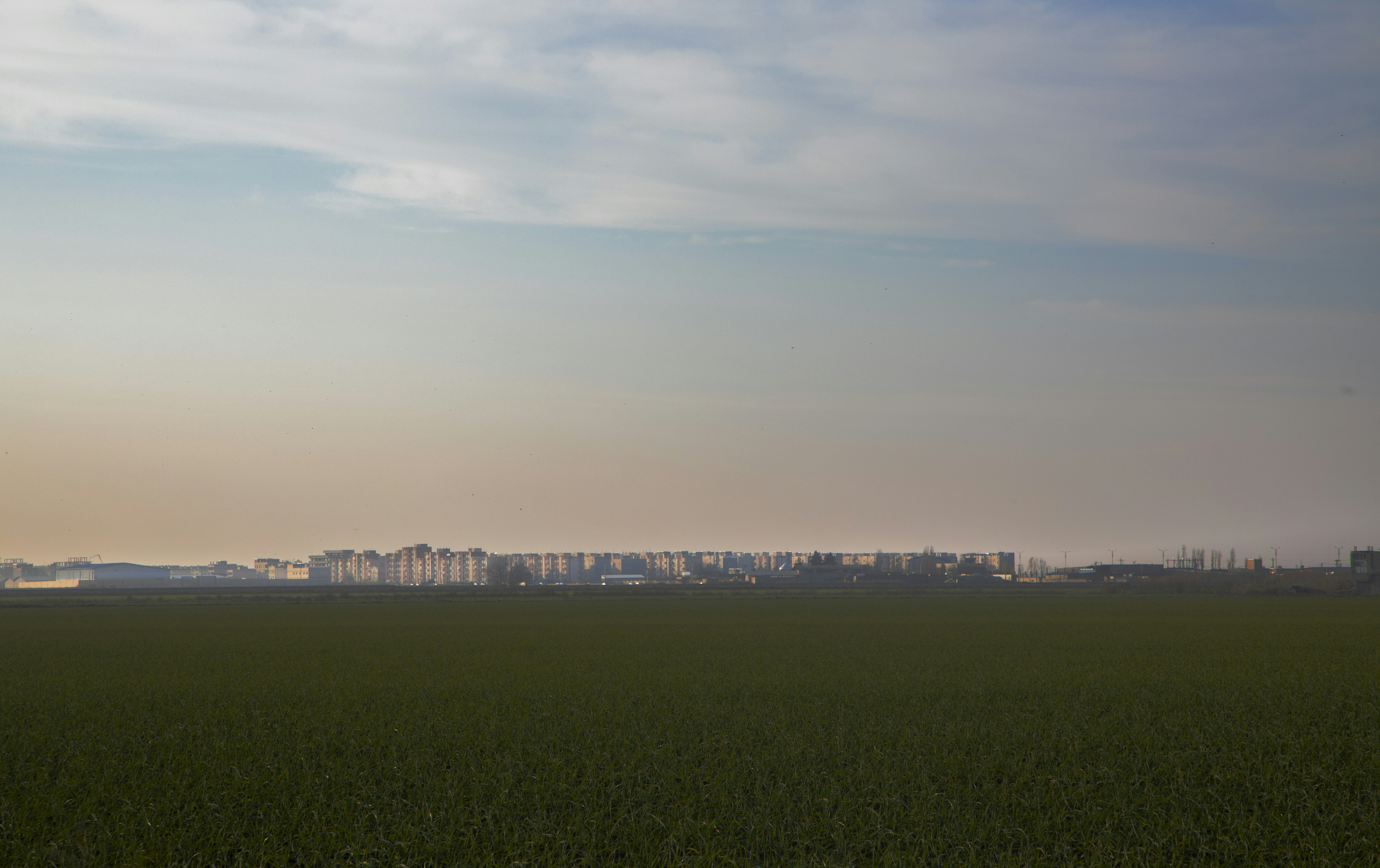 A large field of grass with a city in the distance photo – Free ...