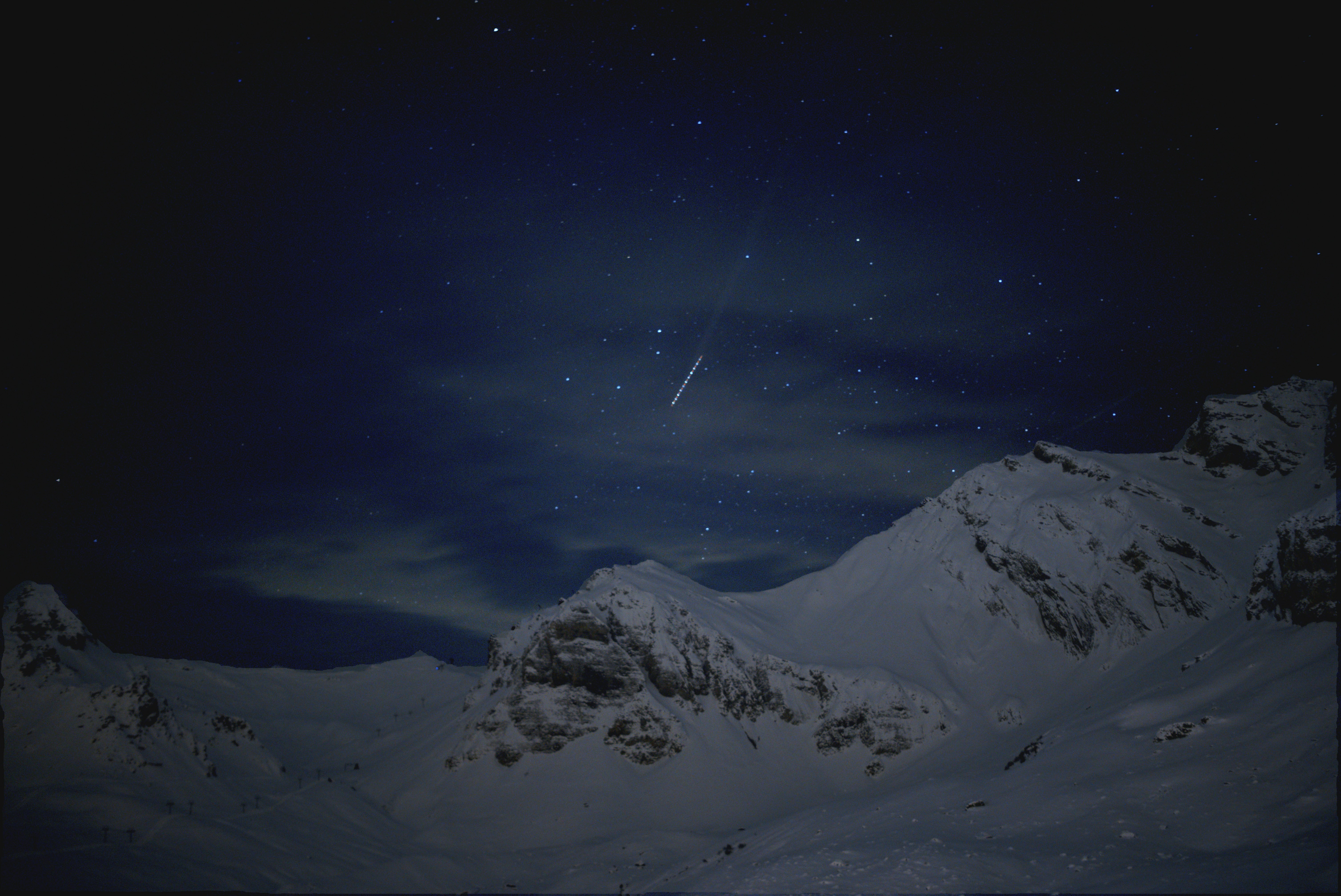 Meteor Arc Over the Snowbound Spine of Alpine Peaks at Night