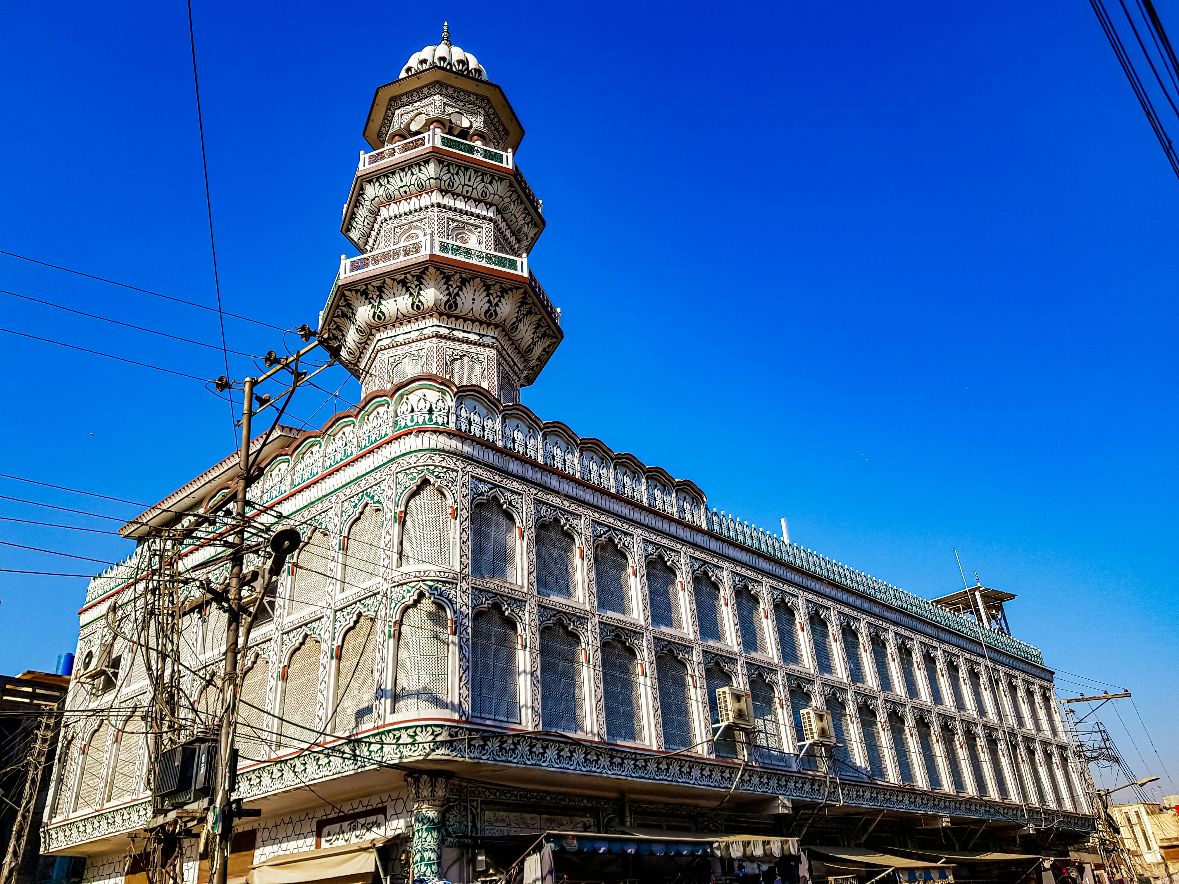 Historic building featuring intricate architectural details and a prominent minaret against a clear blue sky.