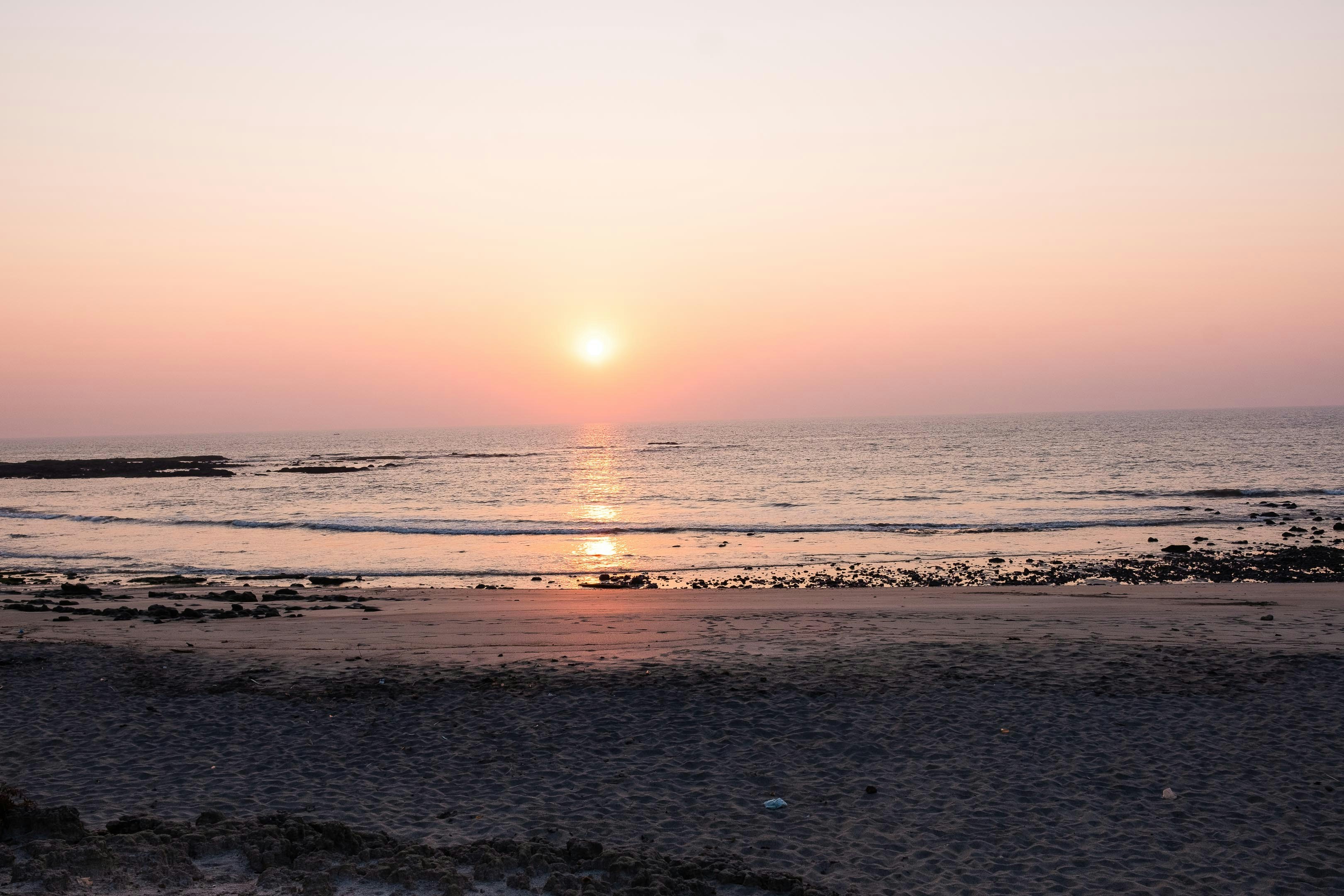 The sun is setting over the ocean on the beach photo – Free Shekhadi ...
