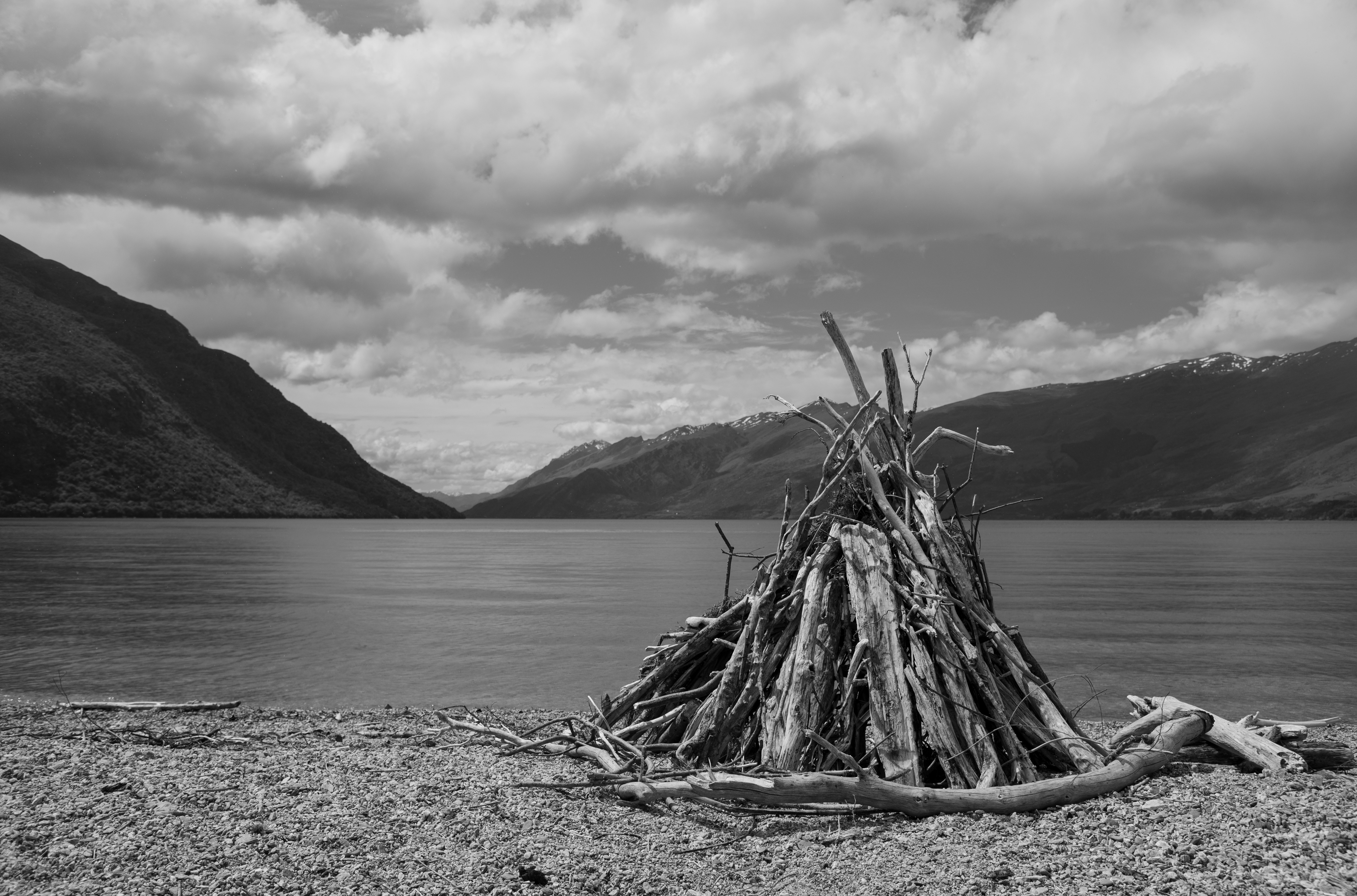 Stone-built beacon: a driftwood tipi on a quiet lakeshore