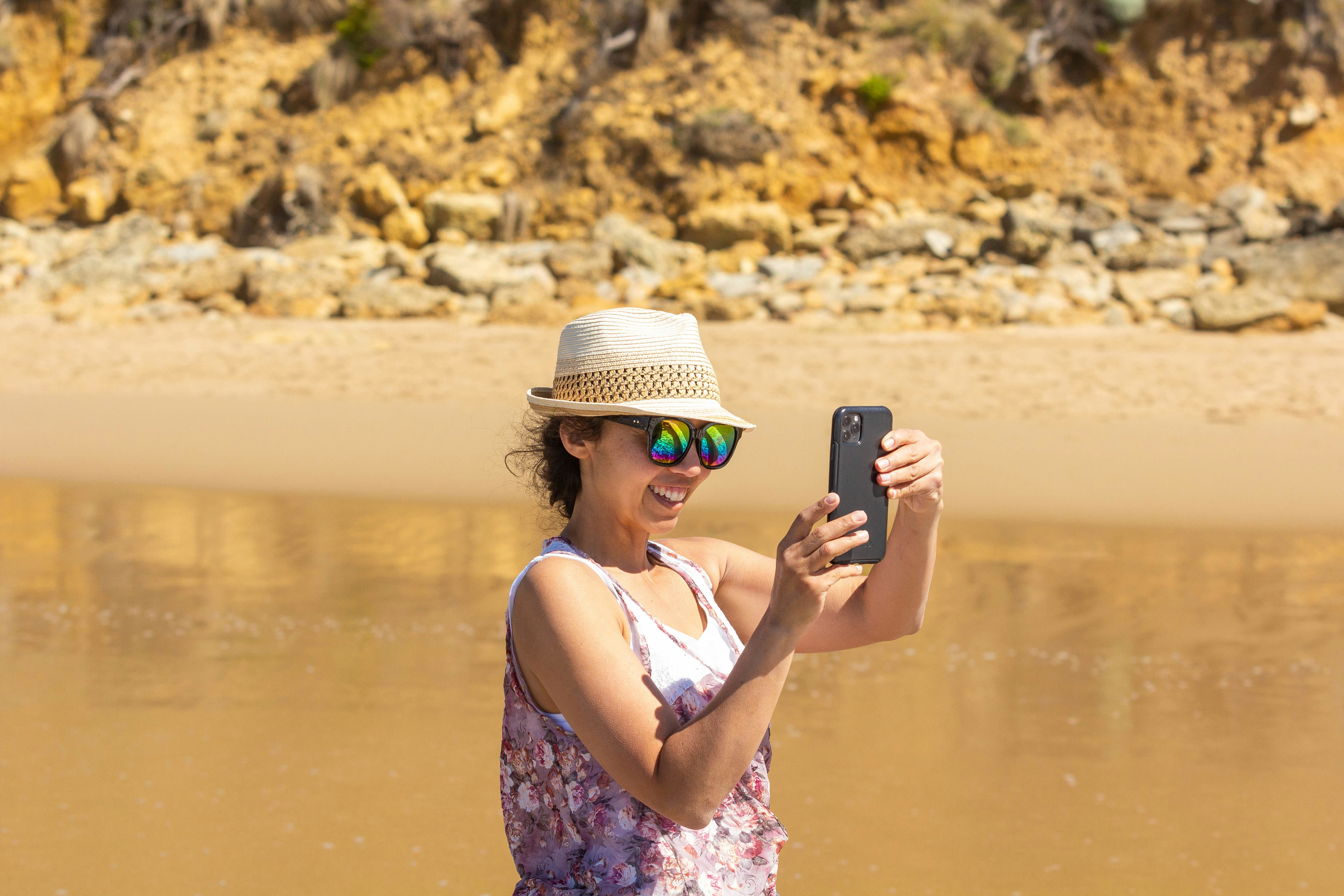 Selfie at the Sunlit Shore: Straw Hat, Mirrored Lenses, and a Quiet Beach Portrait