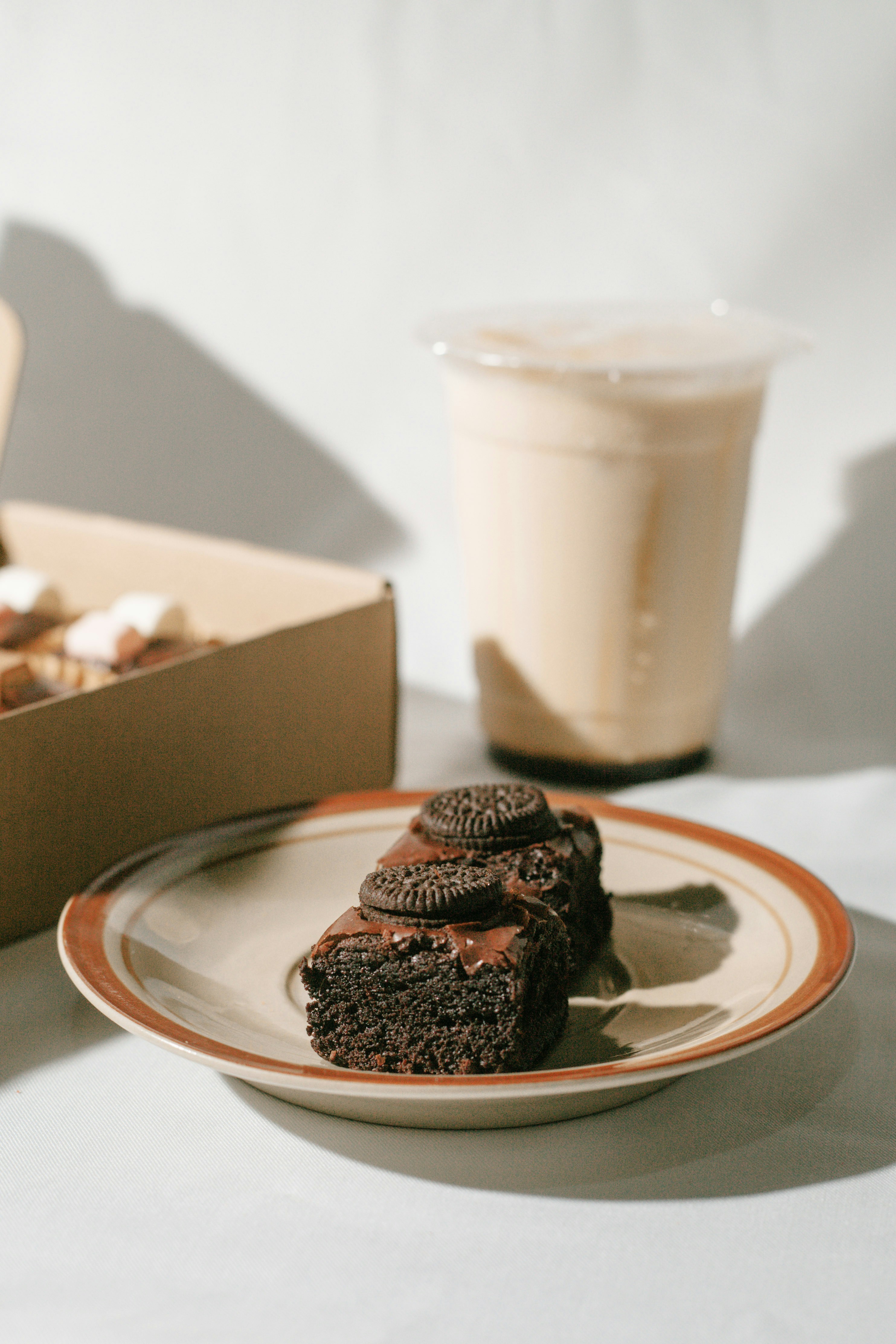Oreo-Crowned Brownies on a Ceramic Plate with a Soft Iced-Coffee Backdrop