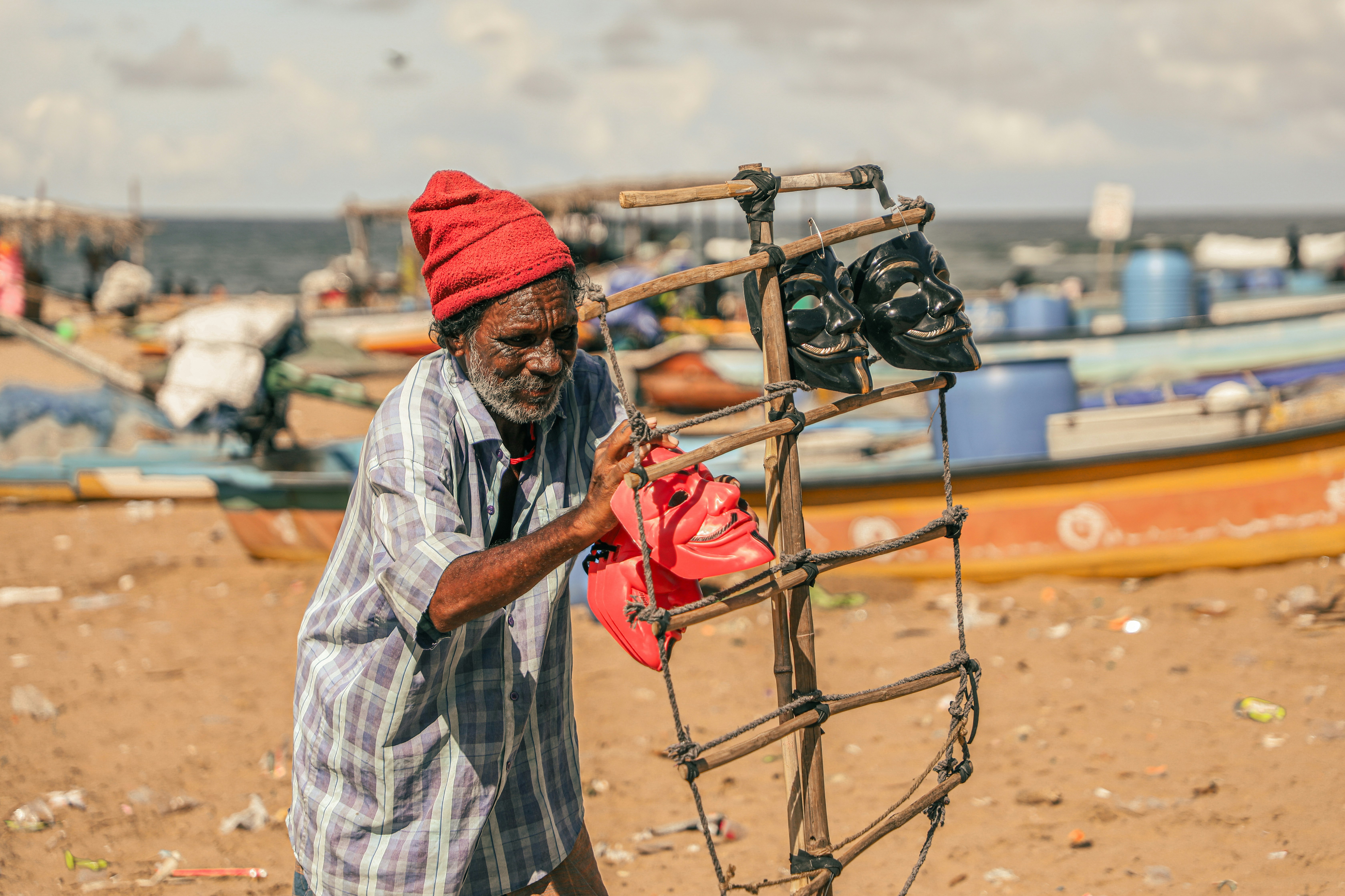 A man standing on a beach next to a bunch of boats photo – Free People ...