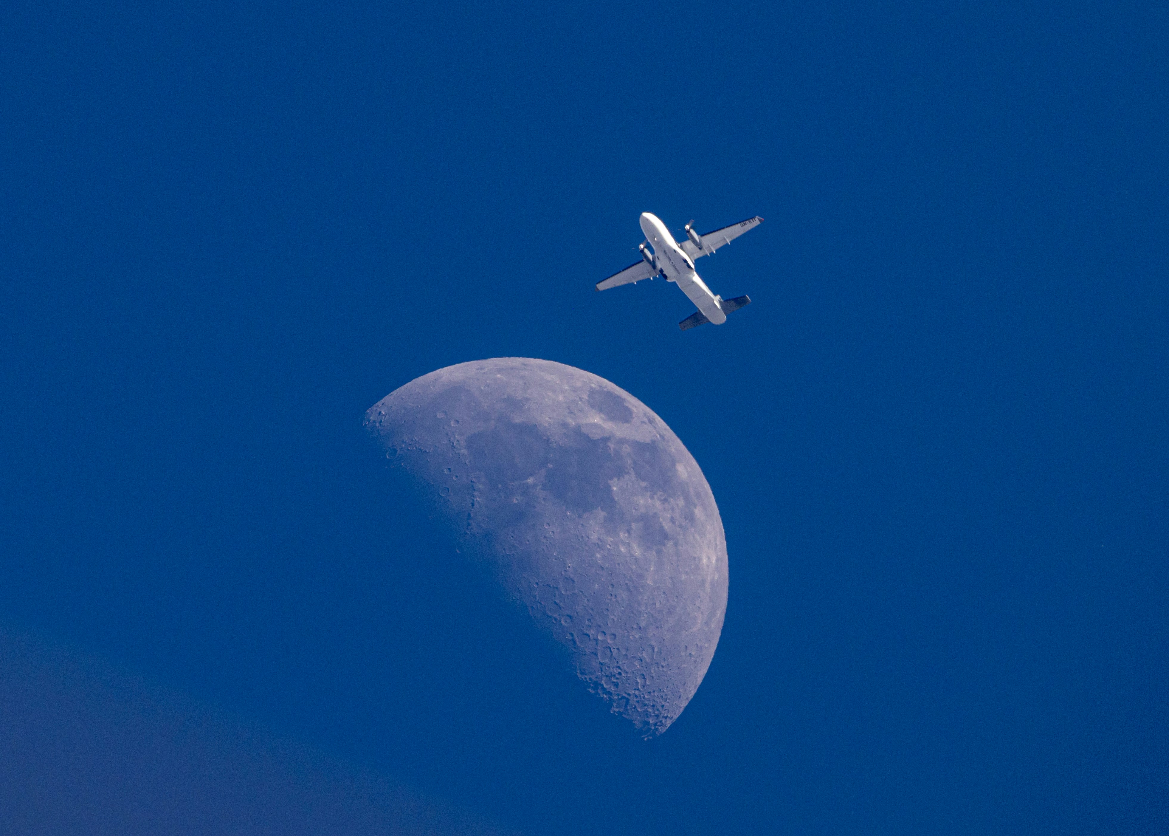 A plane flying over a half moon in the sky photo – Free Ciudad de ...