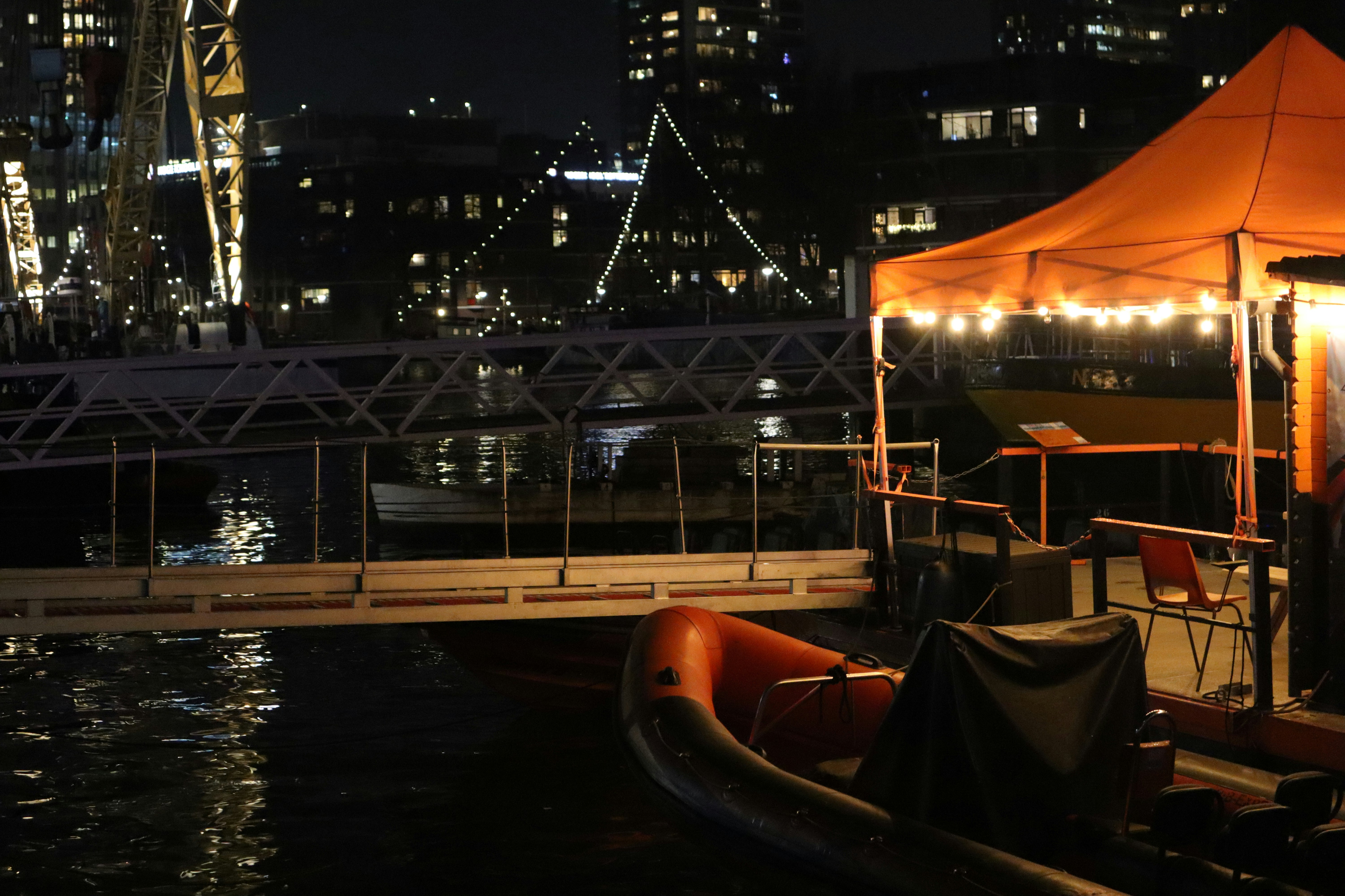Night Harbor: Orange Canopy Illuminates the Dock by City Reflections