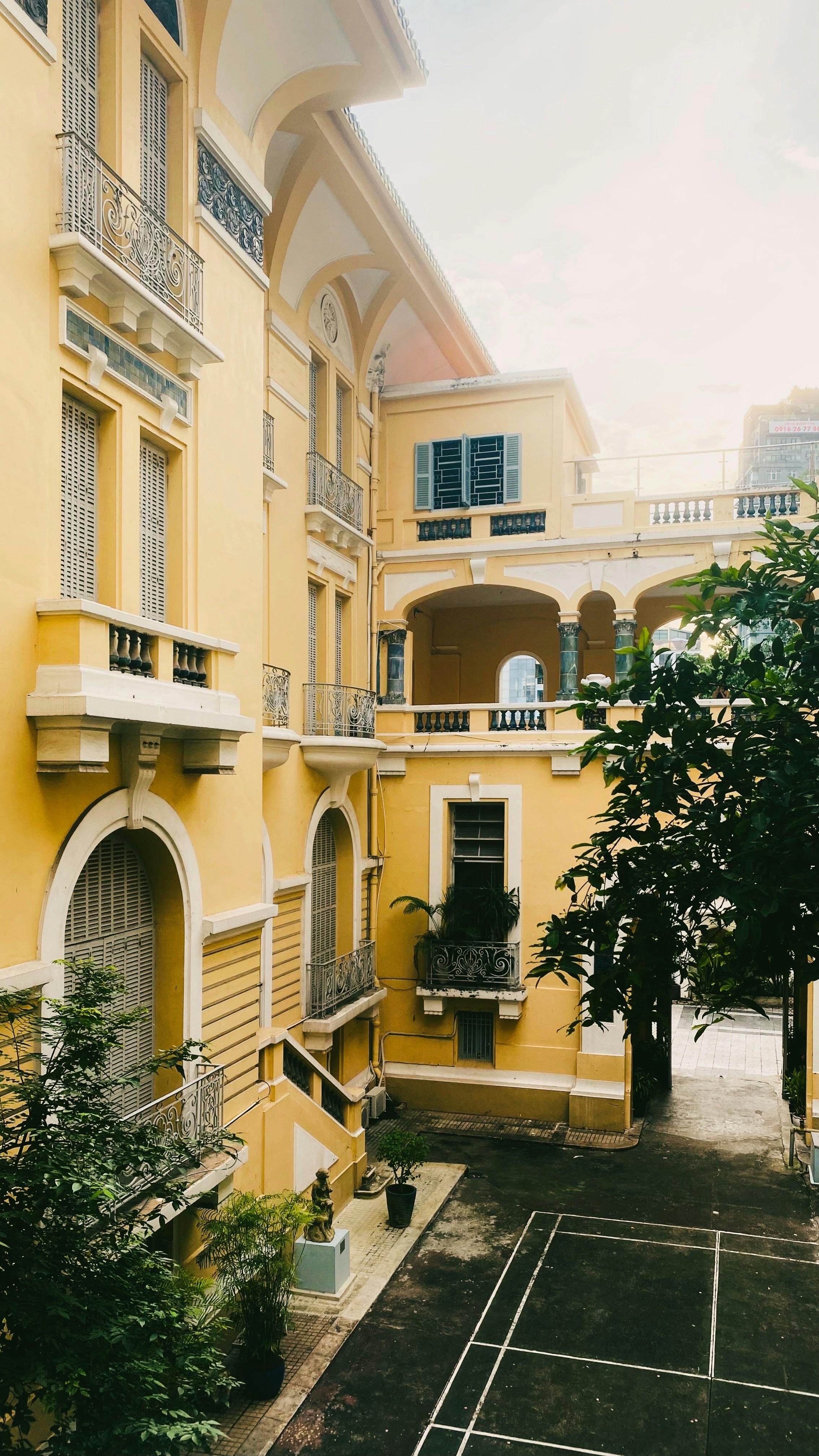 Sunlit Arcades: A Yellow Courtyard of Arches and Ironwork