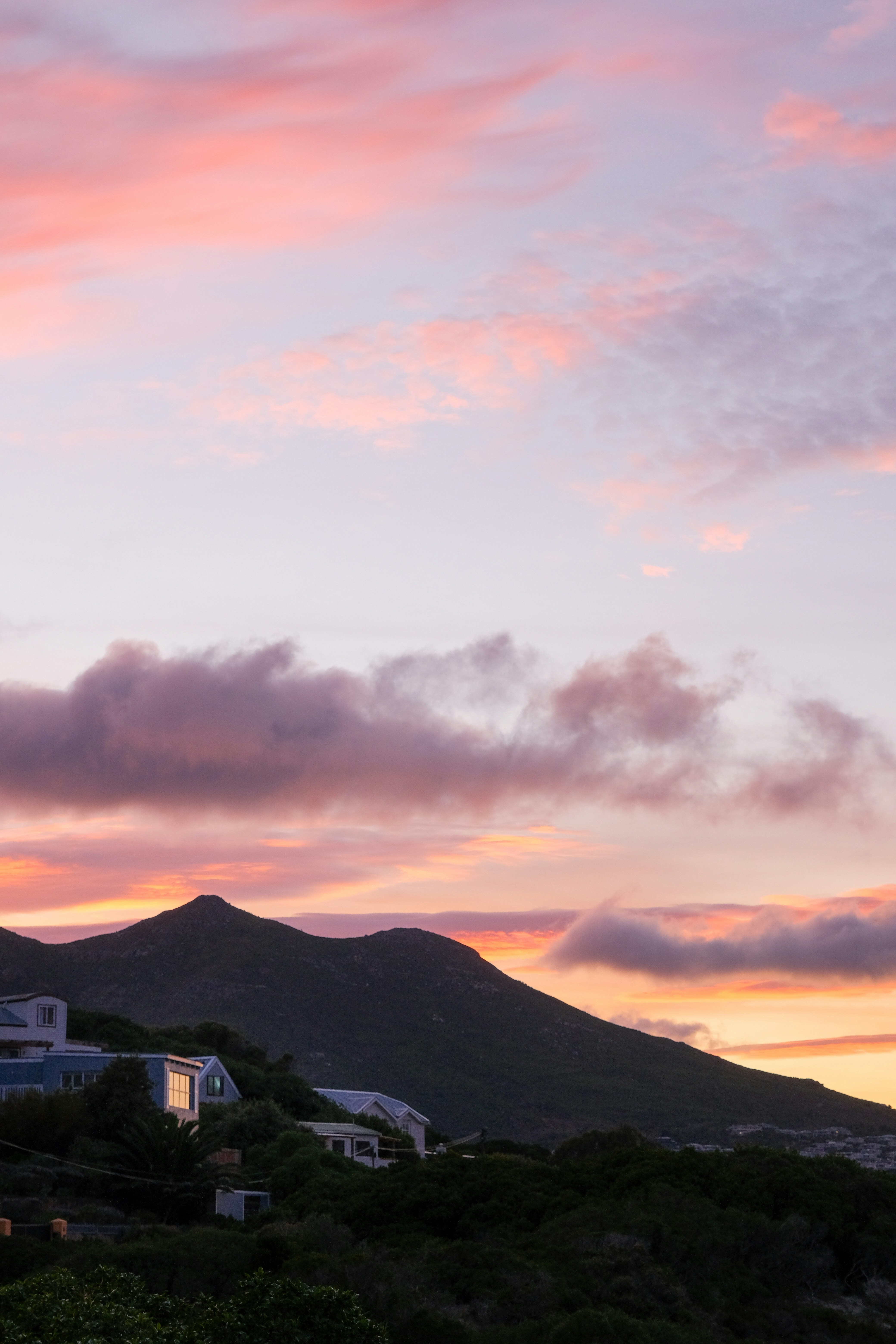 Dusk over a hillside village as pink clouds cradle the mountain silhouette