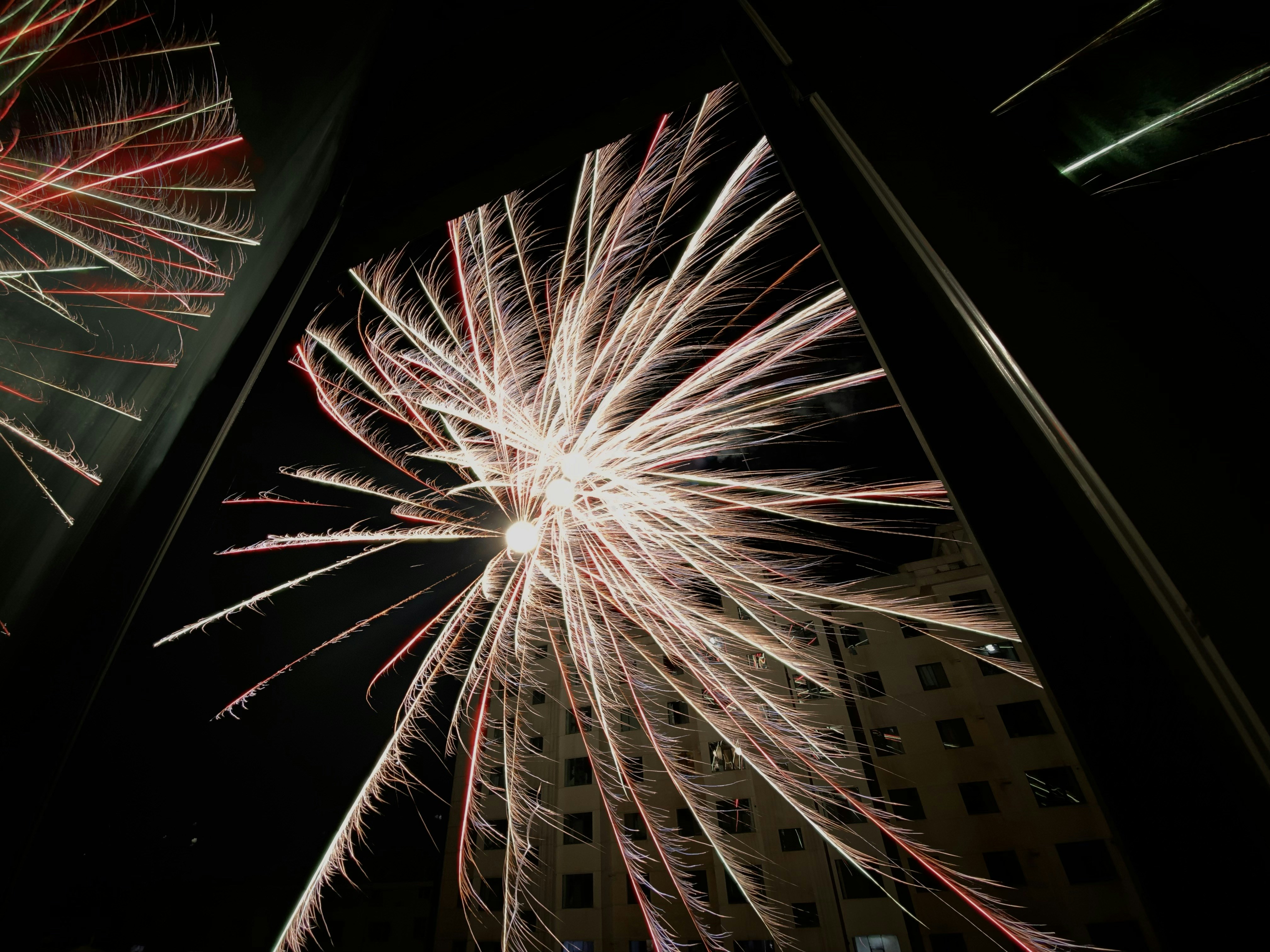 Night Firework Bloom Framed by Urban Angles