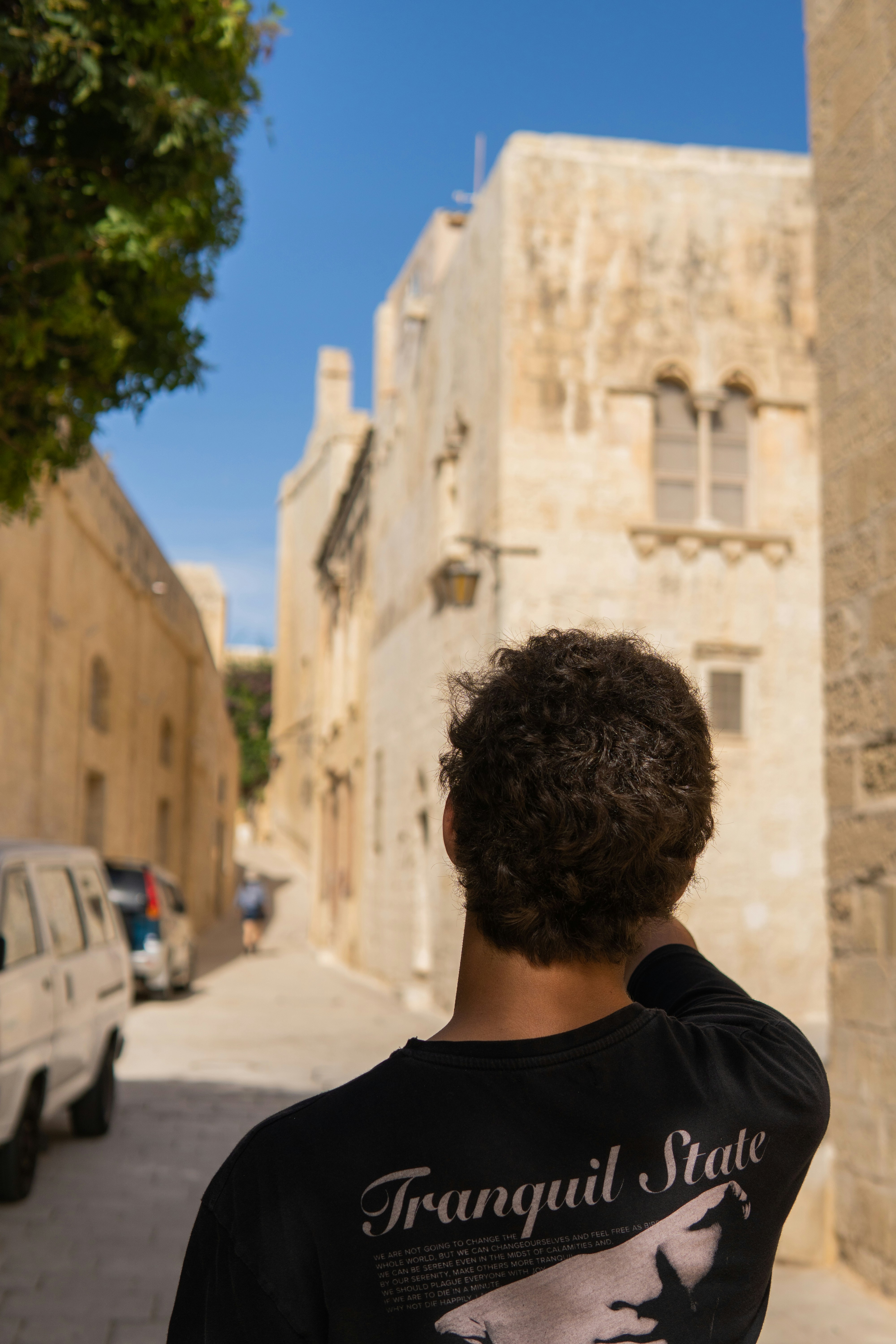 Sunlit Limestone Alley Portrait: Back of the Head in a Quiet Street