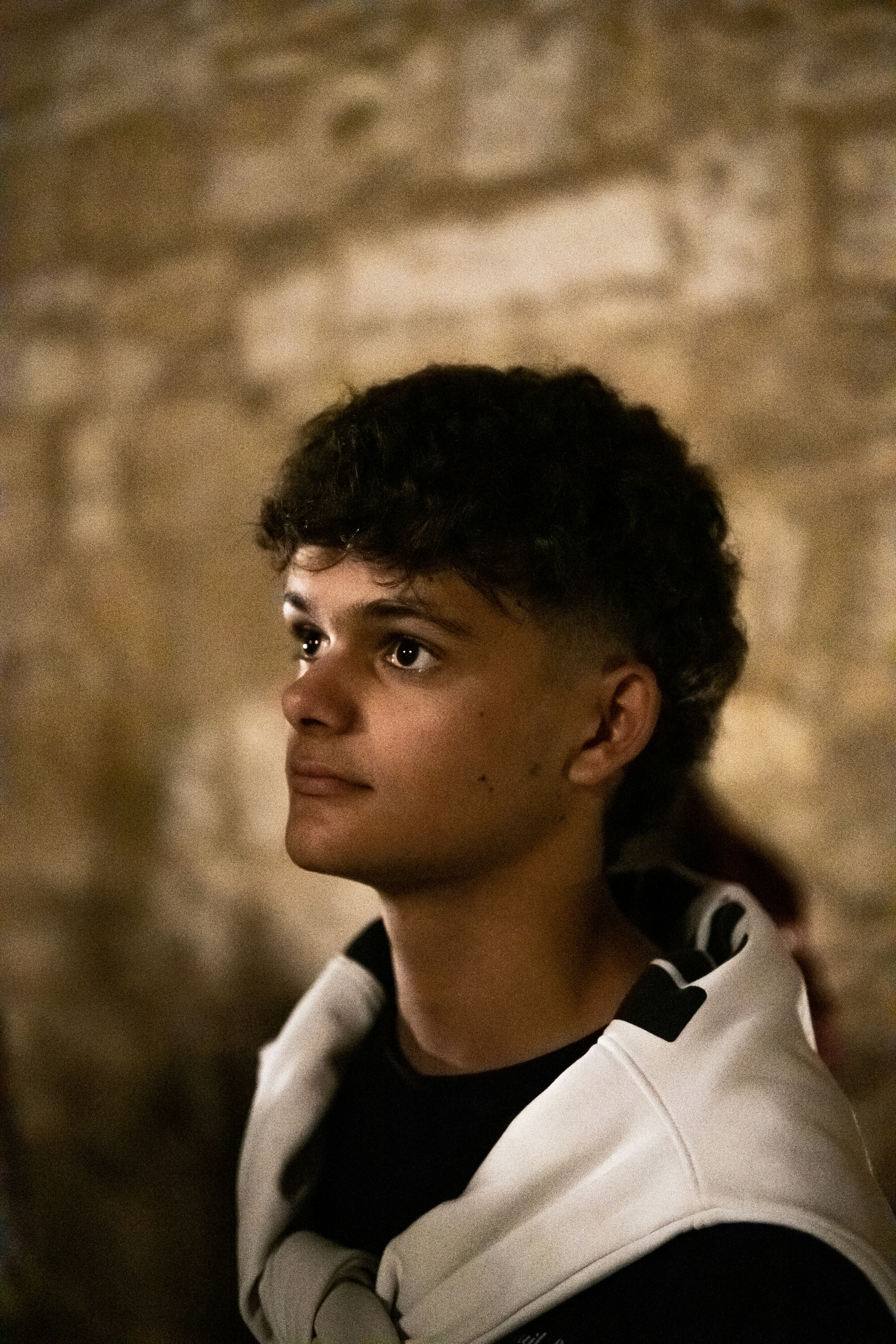 Gilded Quiet: A Youthful Gaze Against a Stone-Washed Backdrop