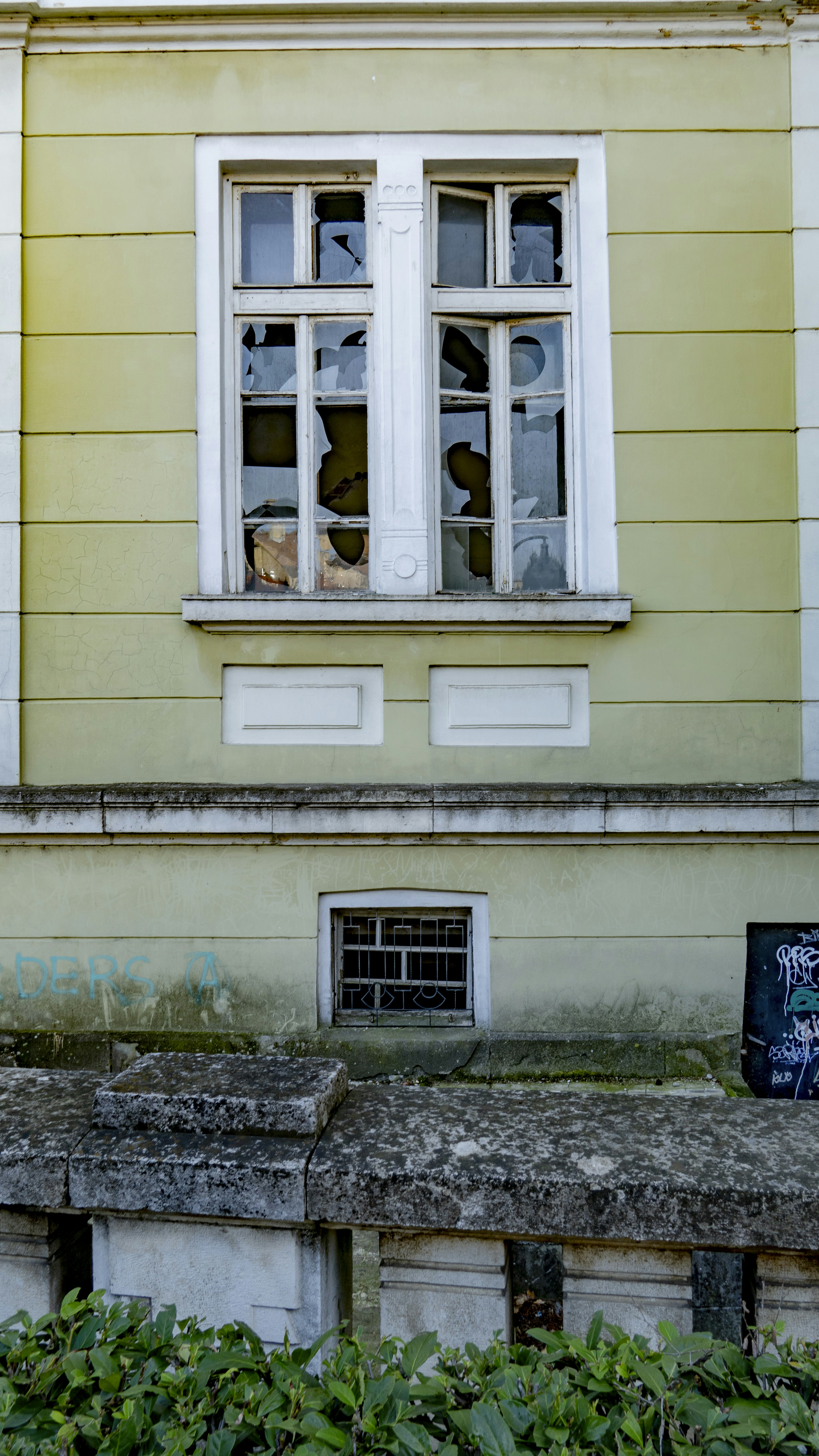 Cracked Glass on a Sunlit Yellow Facade