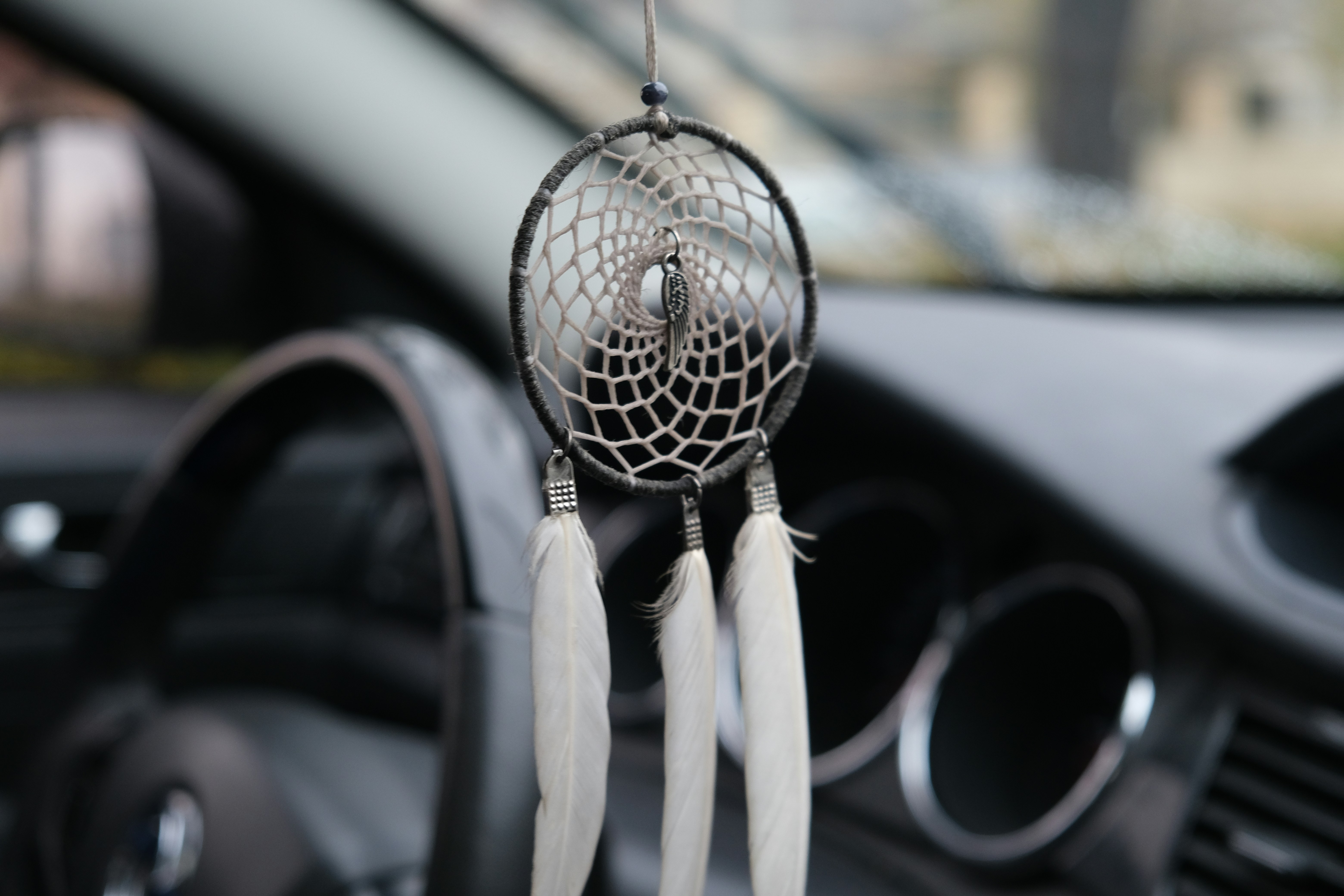 Feathered Focus: Dreamcatcher Dangles Over a Car Dashboard