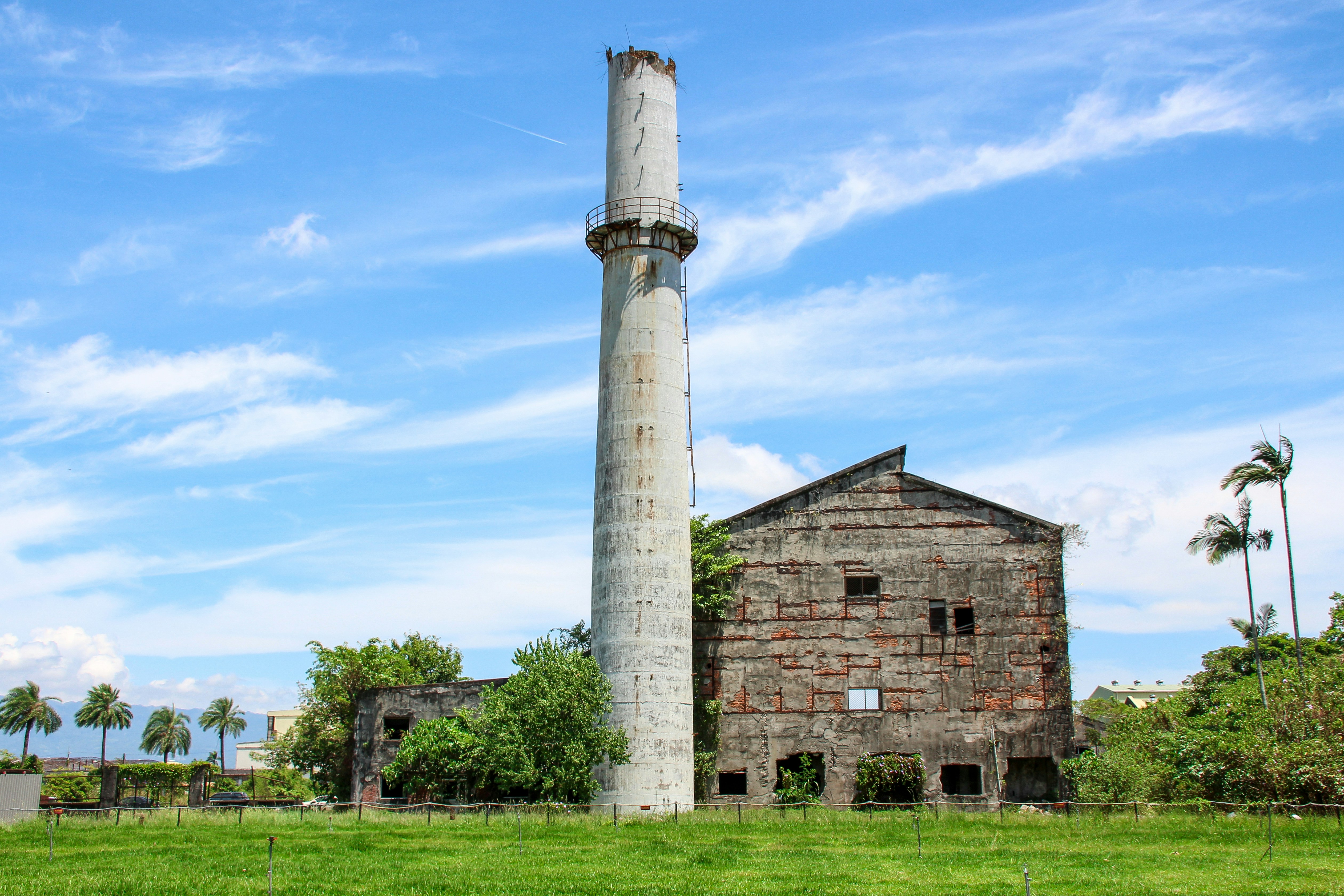The Smokestack's Quiet Gaze Over a Weathered Brick Mill Under a Tropical Sky